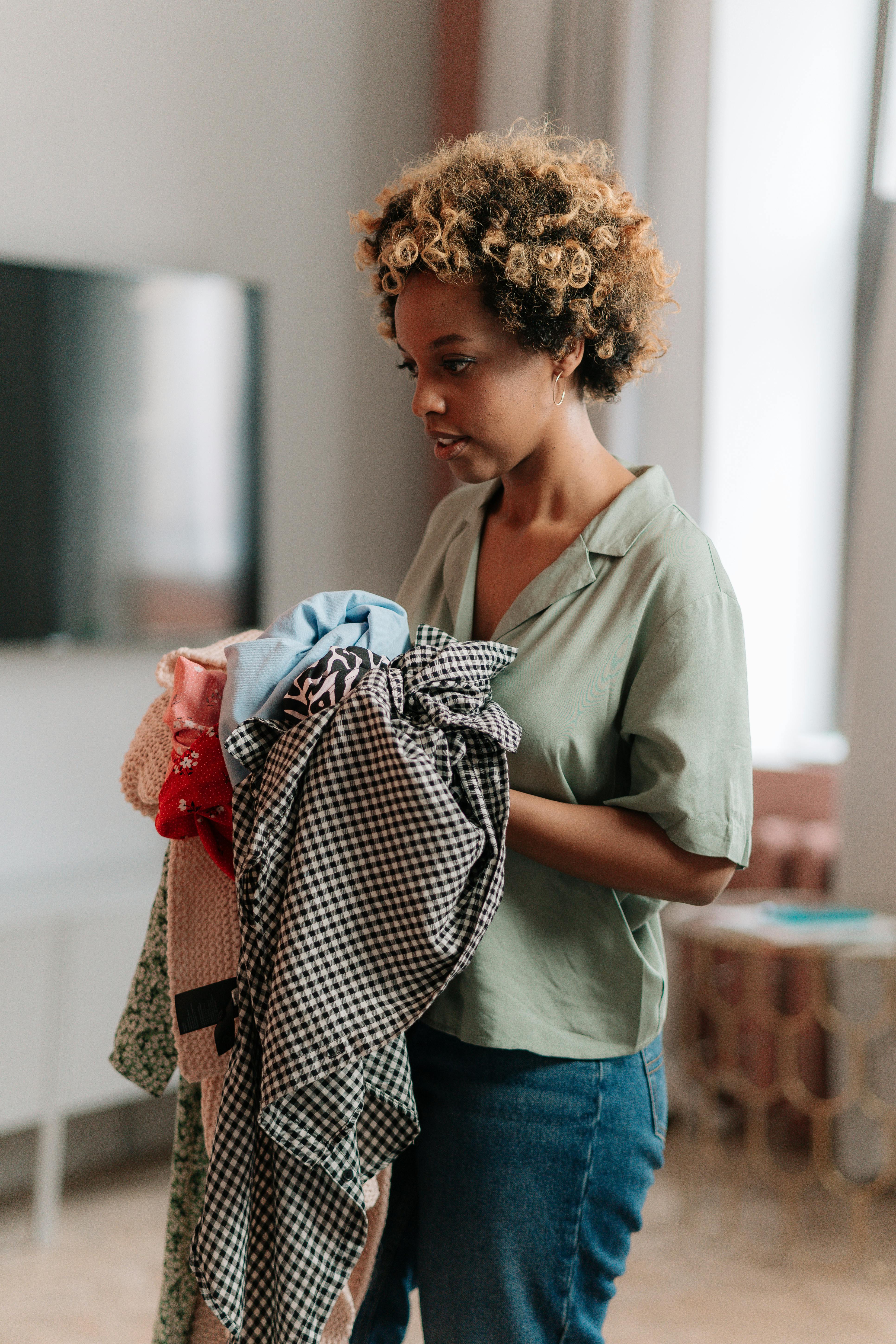Woman Standing and Holding Clothes · Free Stock Photo
