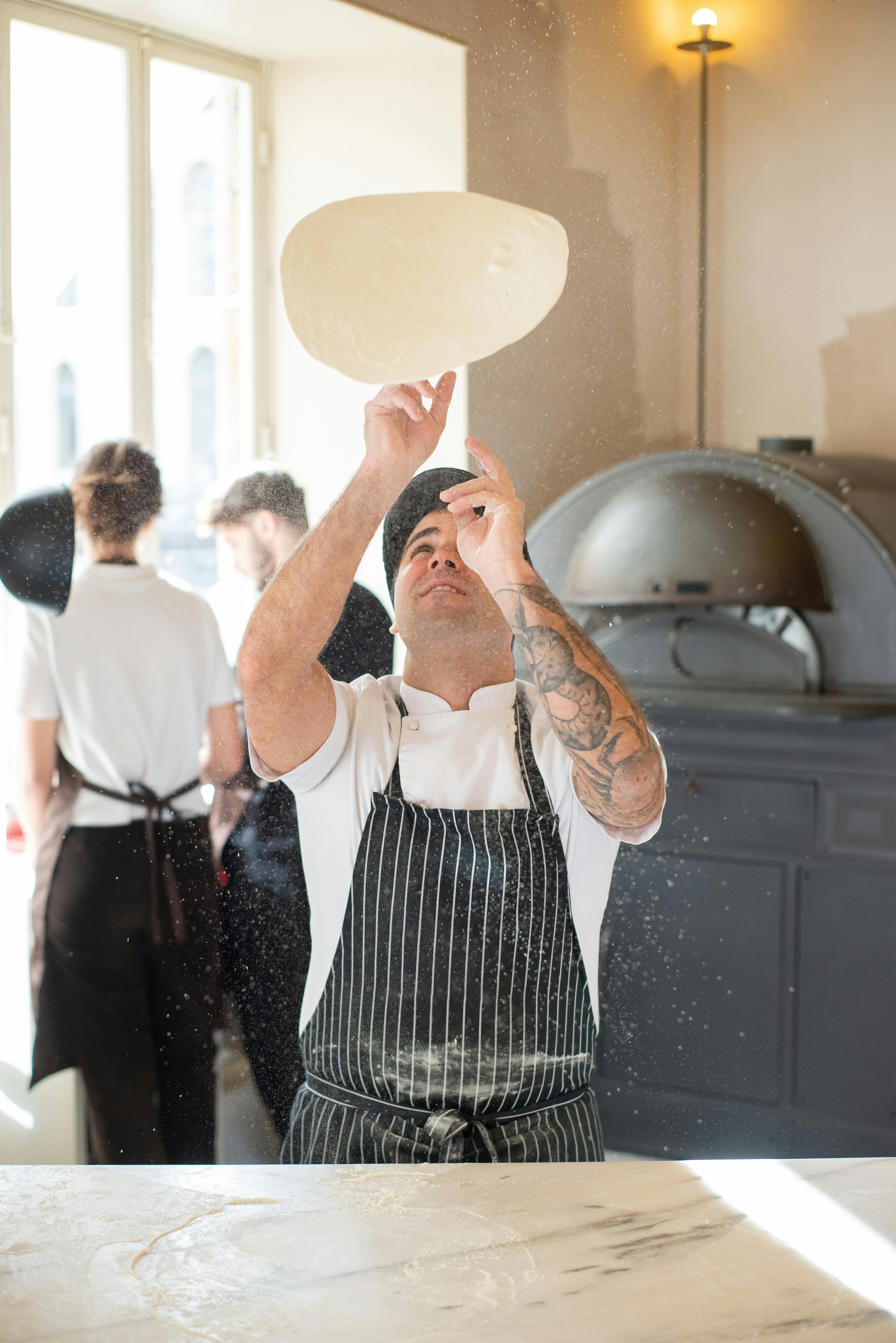 Chef Spinning Dough in a Pizzeria · Free Stock Photo