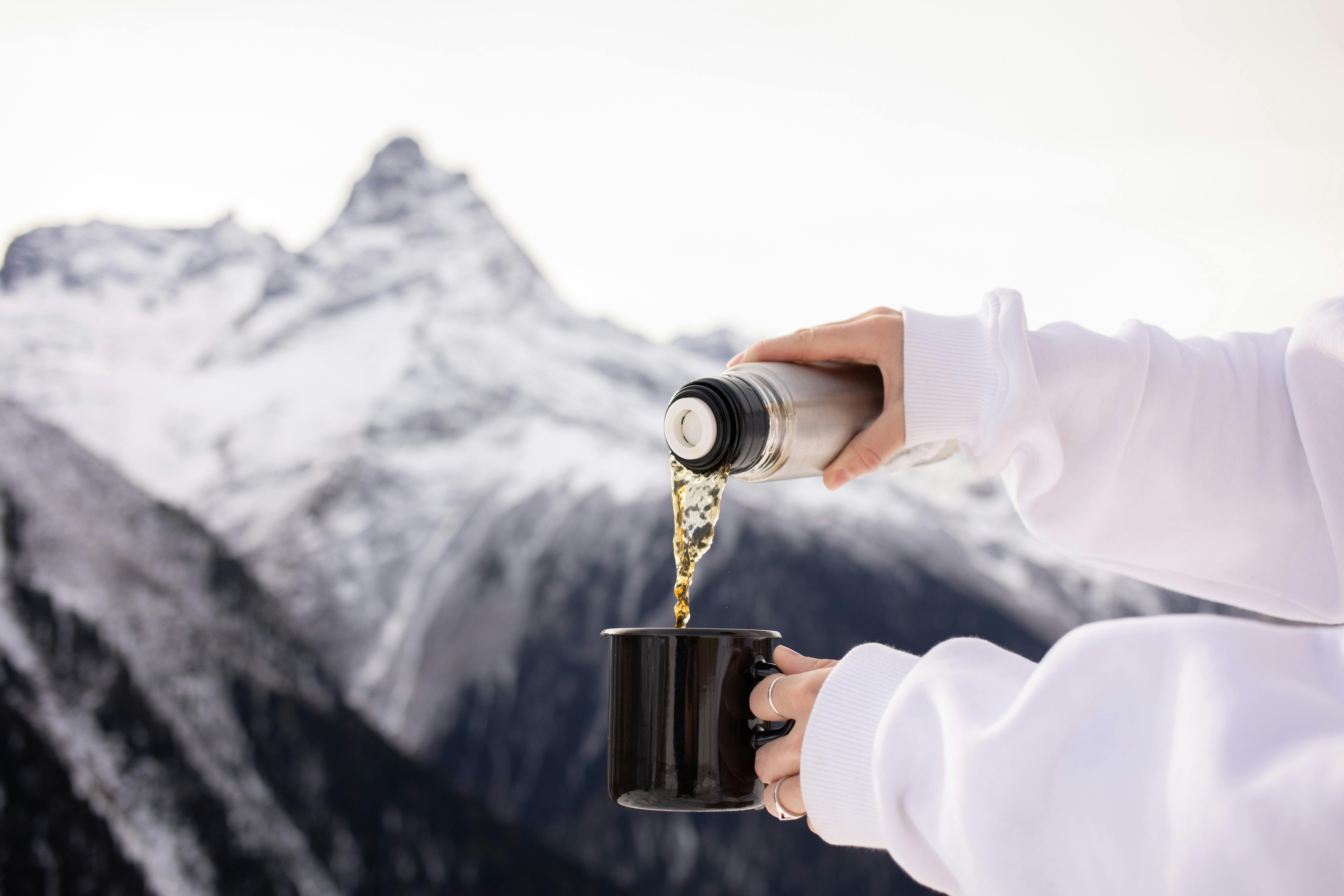 Person Pouring Yellow Drink on Black Ceramic Mug · Free Stock Photo