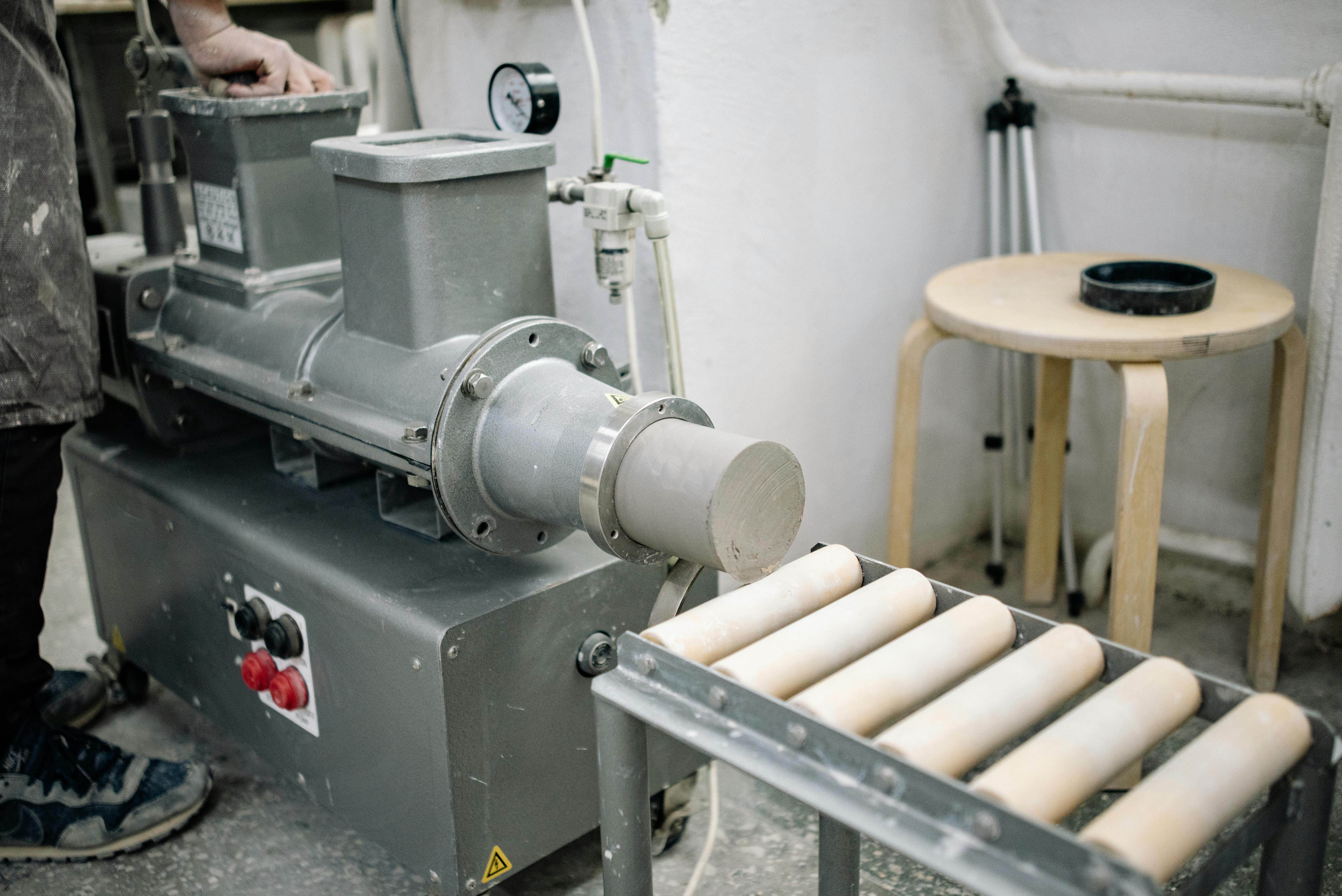 Man Operating a Machine Forming a Long Roll of Clay · Free Stock Photo