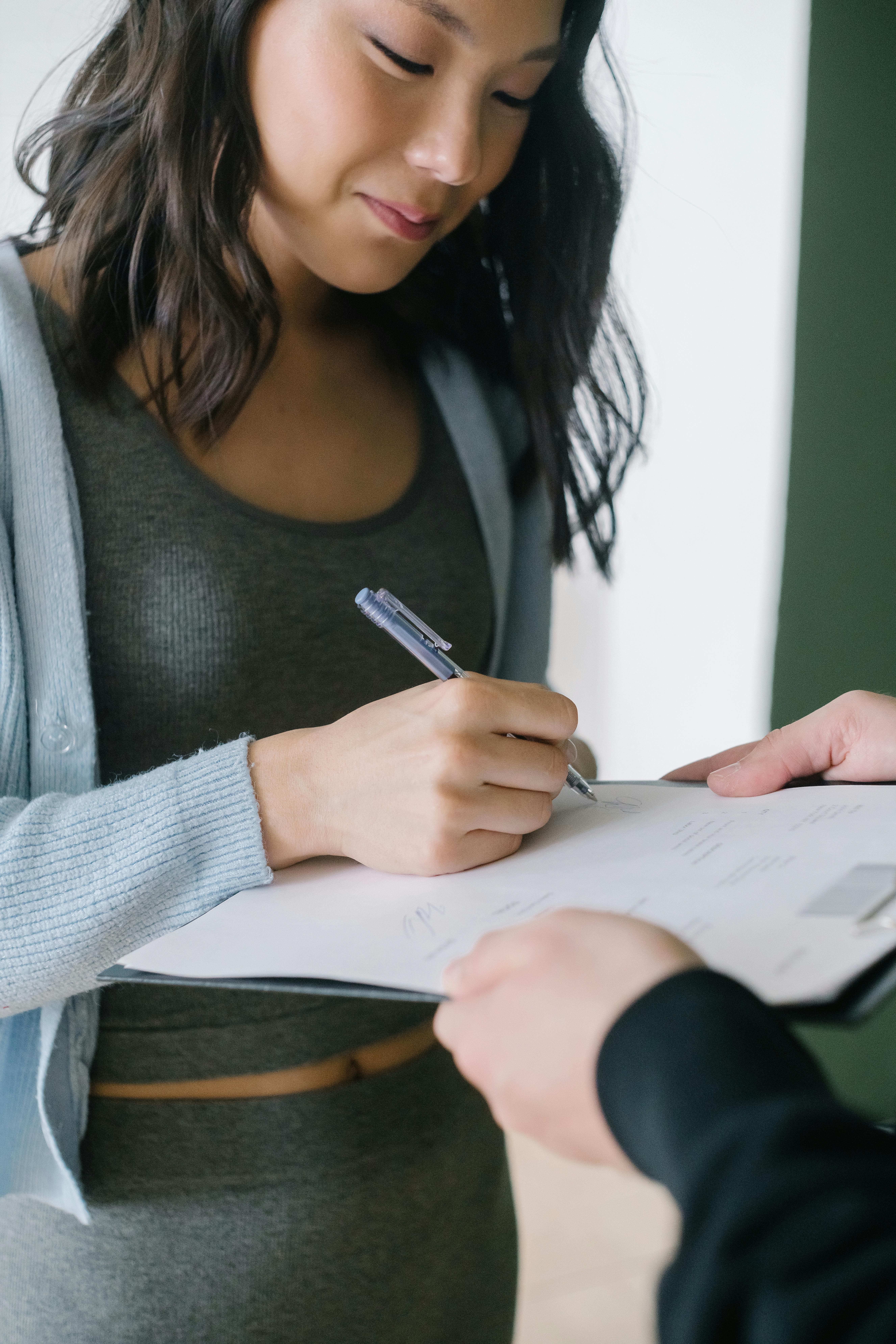 A Woman Signing a Document · Free Stock Photo