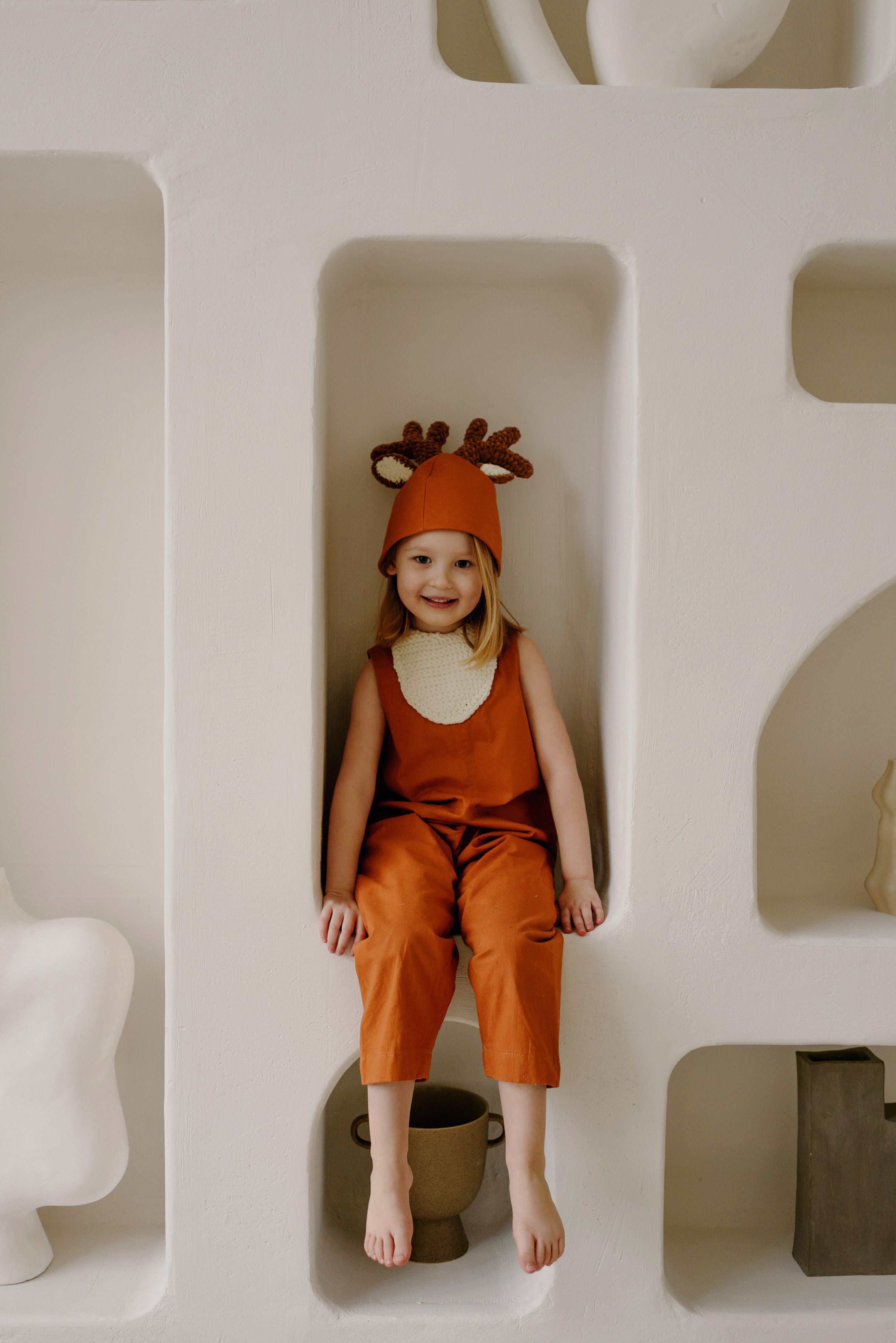 A Girl Wearing a Costume Sitting on a Shelf · Free Stock Photo