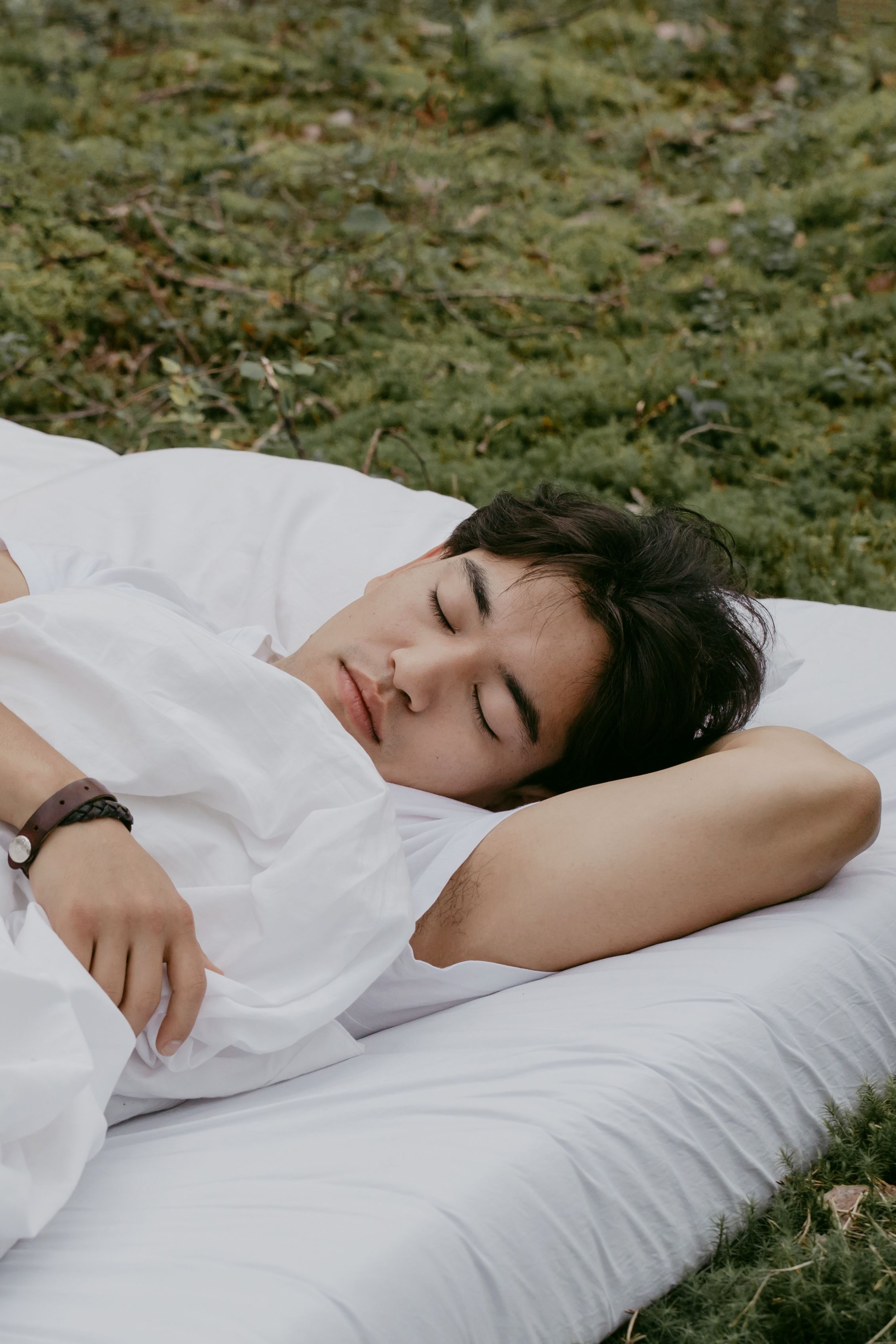 A Man Lying Down on a Mattress over Grass · Free Stock Photo