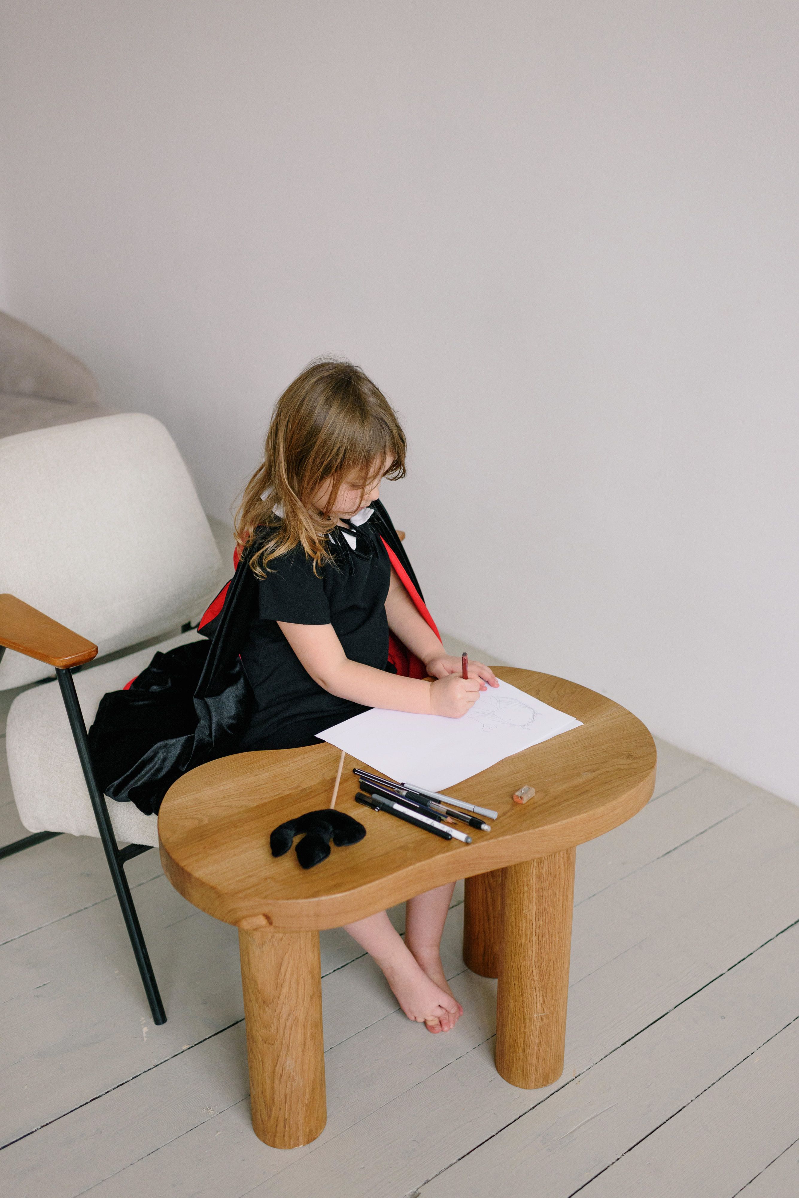A Girl in Black Dress Sitting on White Chair while Drawing on White ...