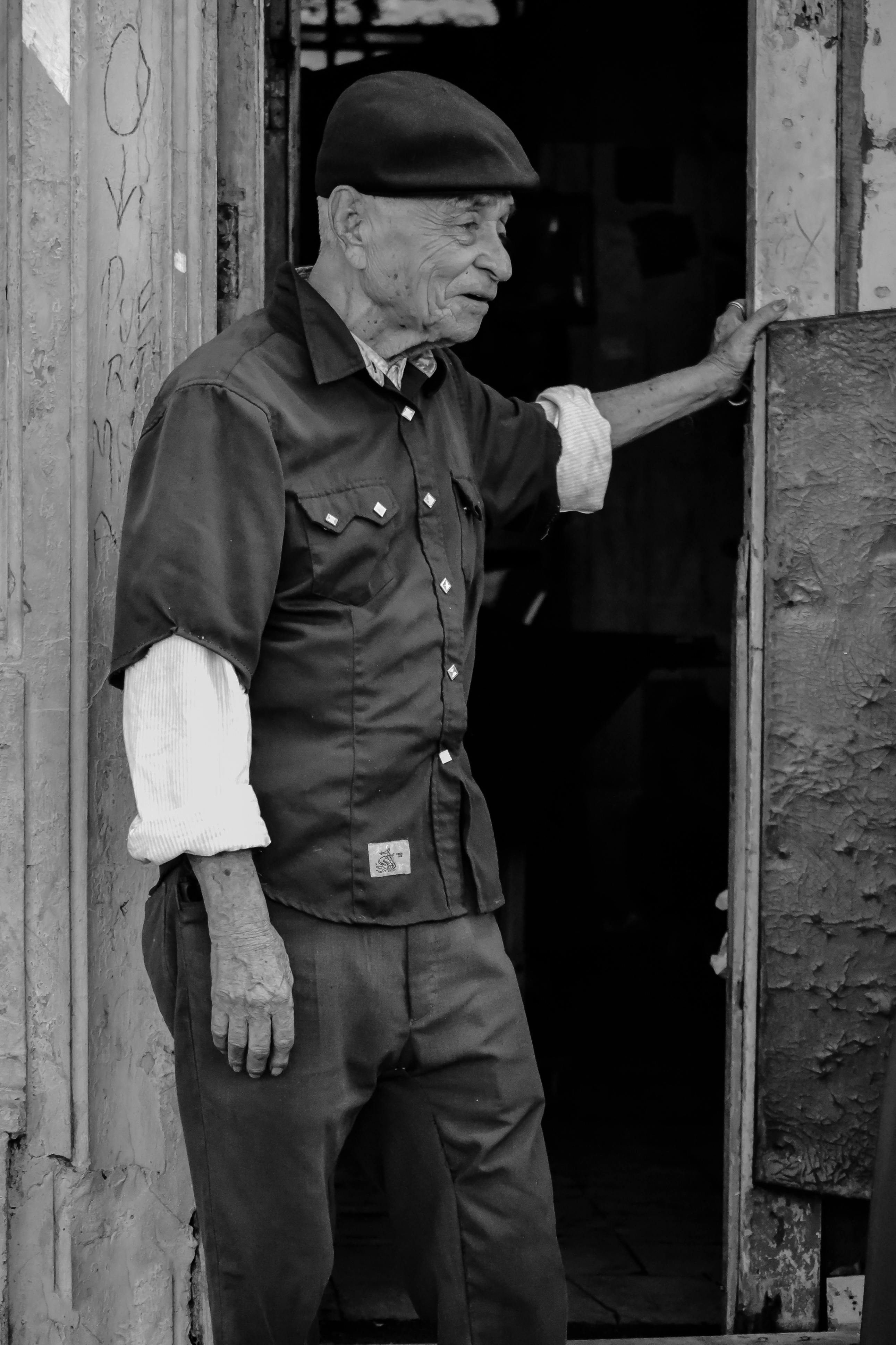 Man in Black Button Up Shirt and Cap Standing Beside Wall · Free Stock ...
