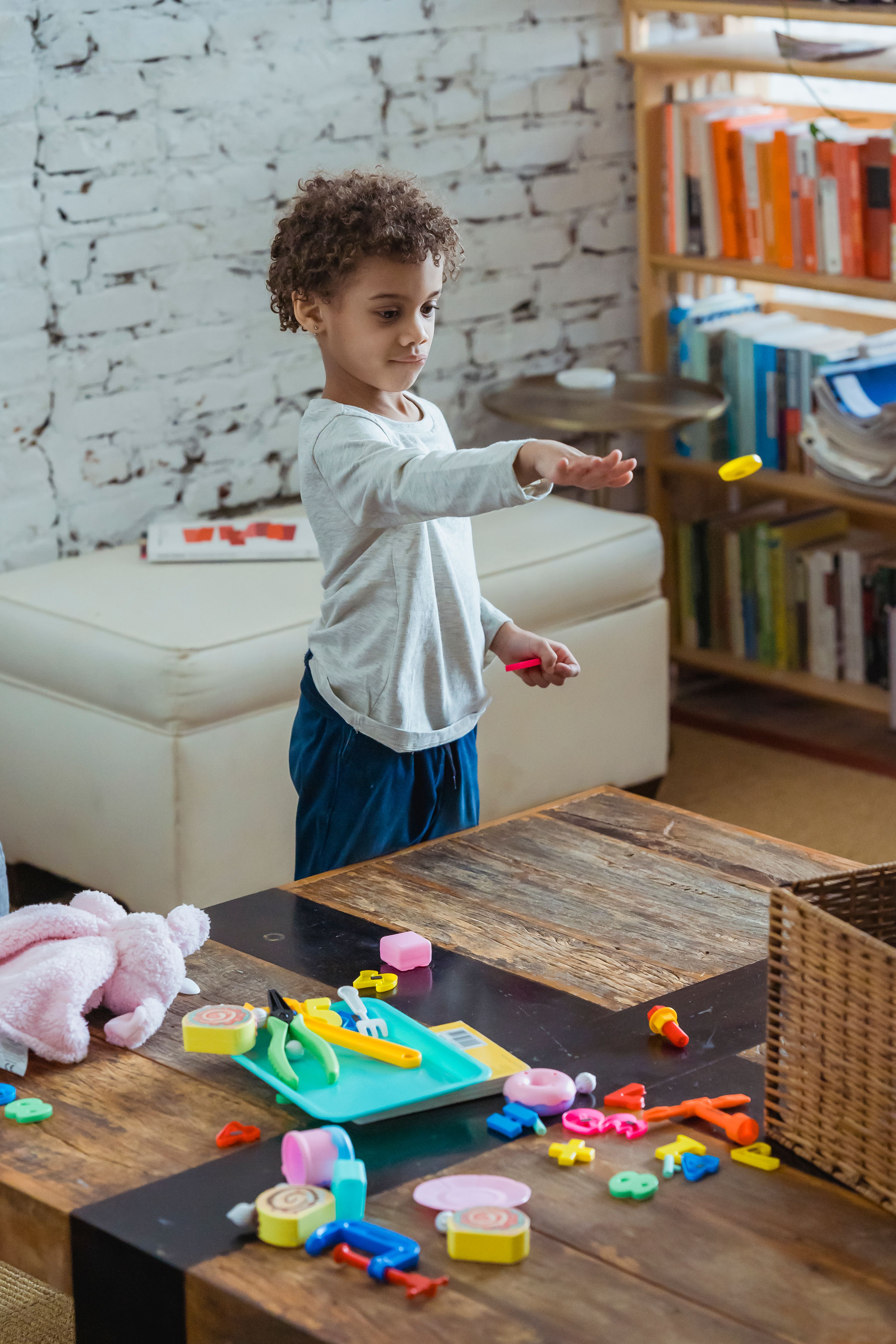 Ethnic boy trying to get hold toy from wicker basket · Free Stock Photo