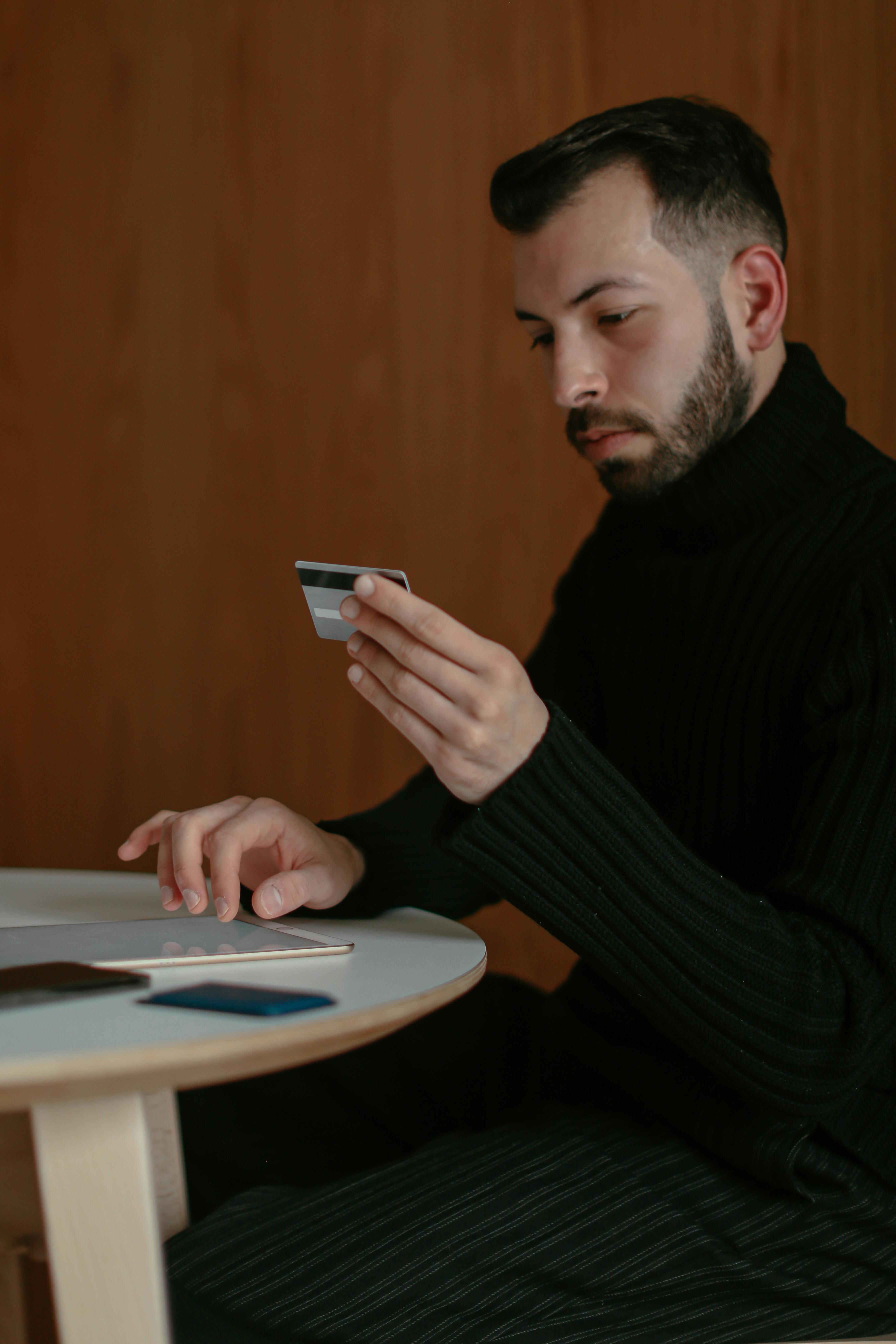 Portrait of a Young Man Checking Credit Card While Online Shopping ...