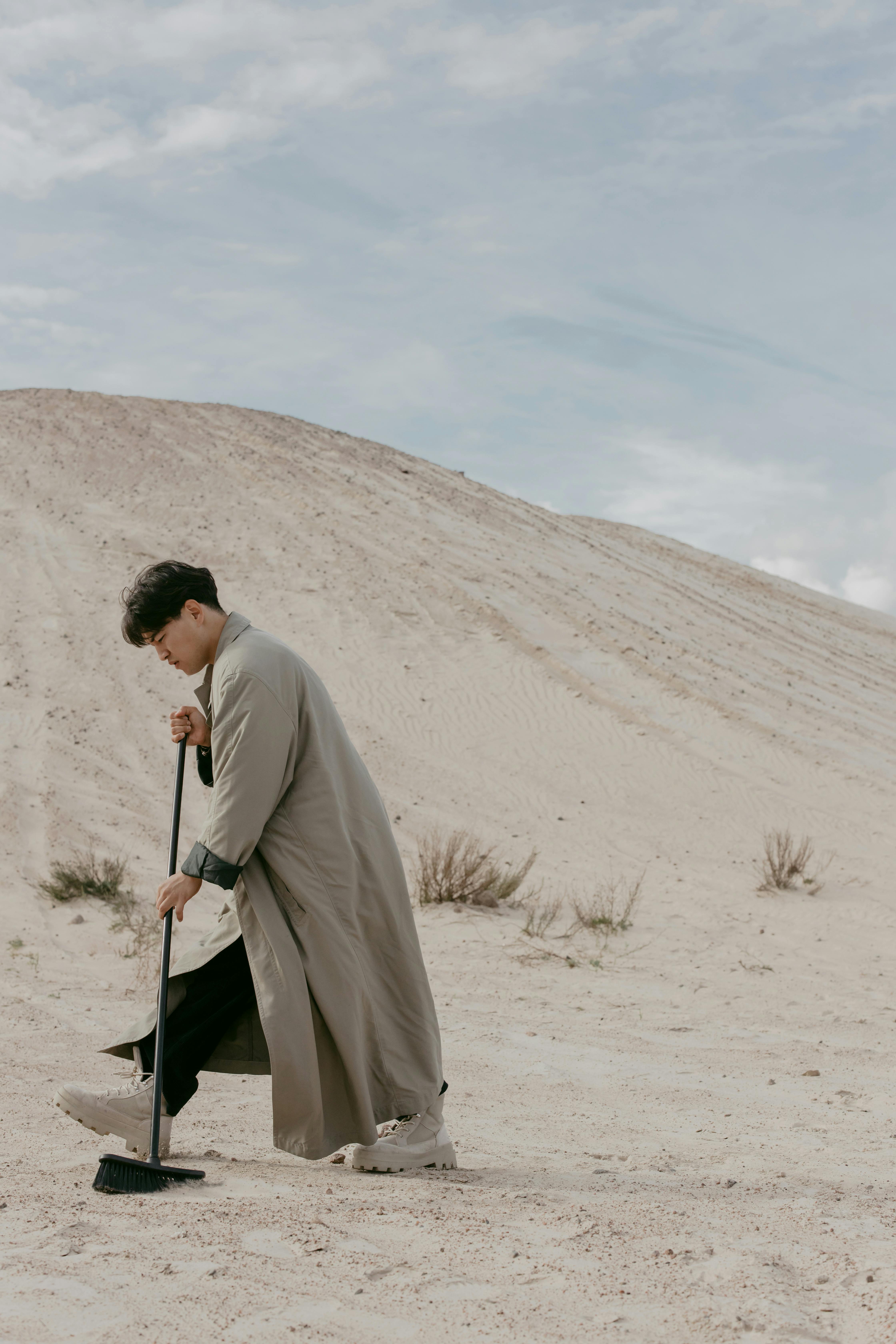 Photograph of a Man Sweeping Sand · Free Stock Photo