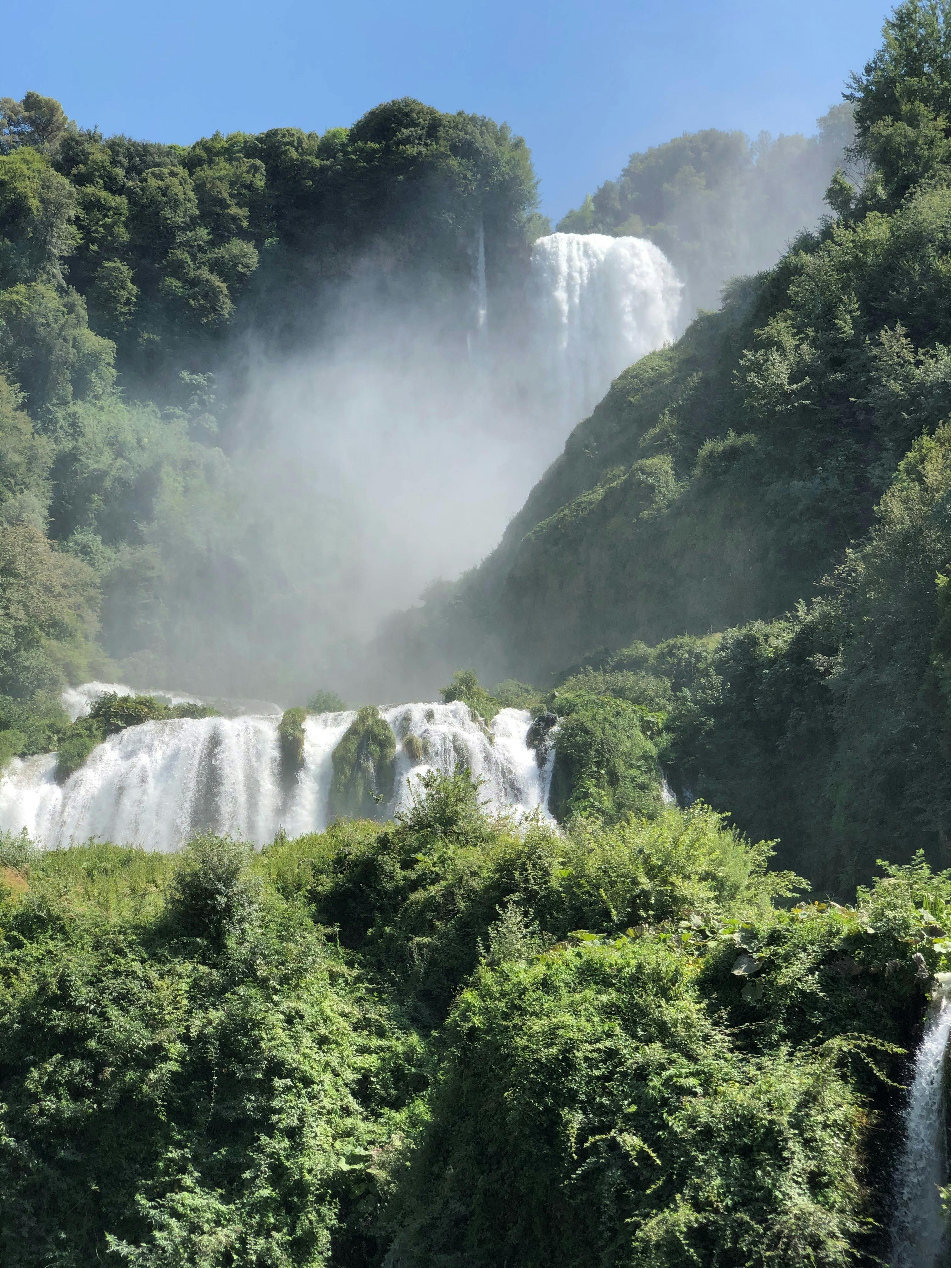 A Waterfalls in the Middle of Green Trees Under the Blue Sky · Free ...