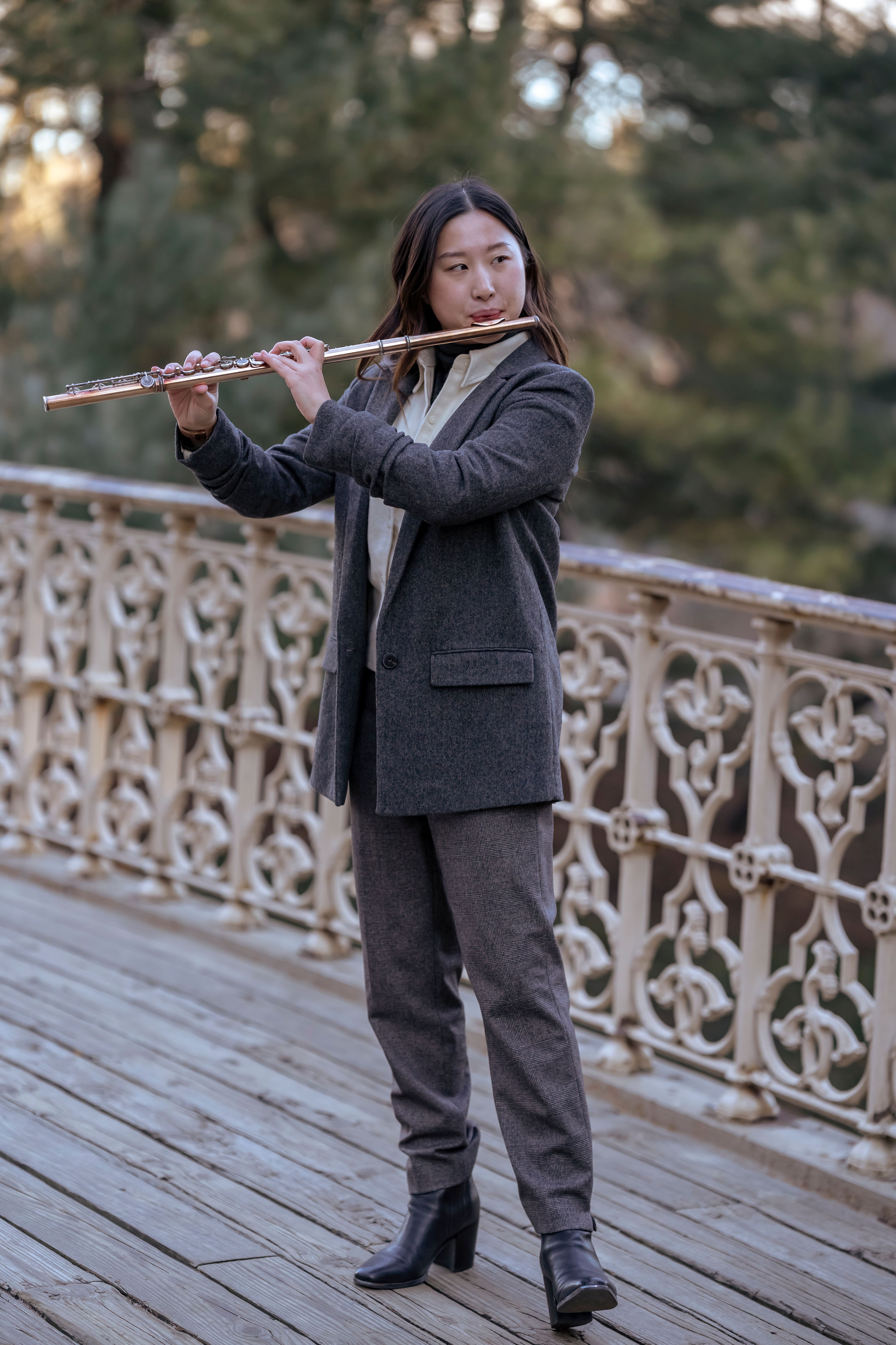 Woman Standing on a Deck Playing a Flute · Free Stock Photo