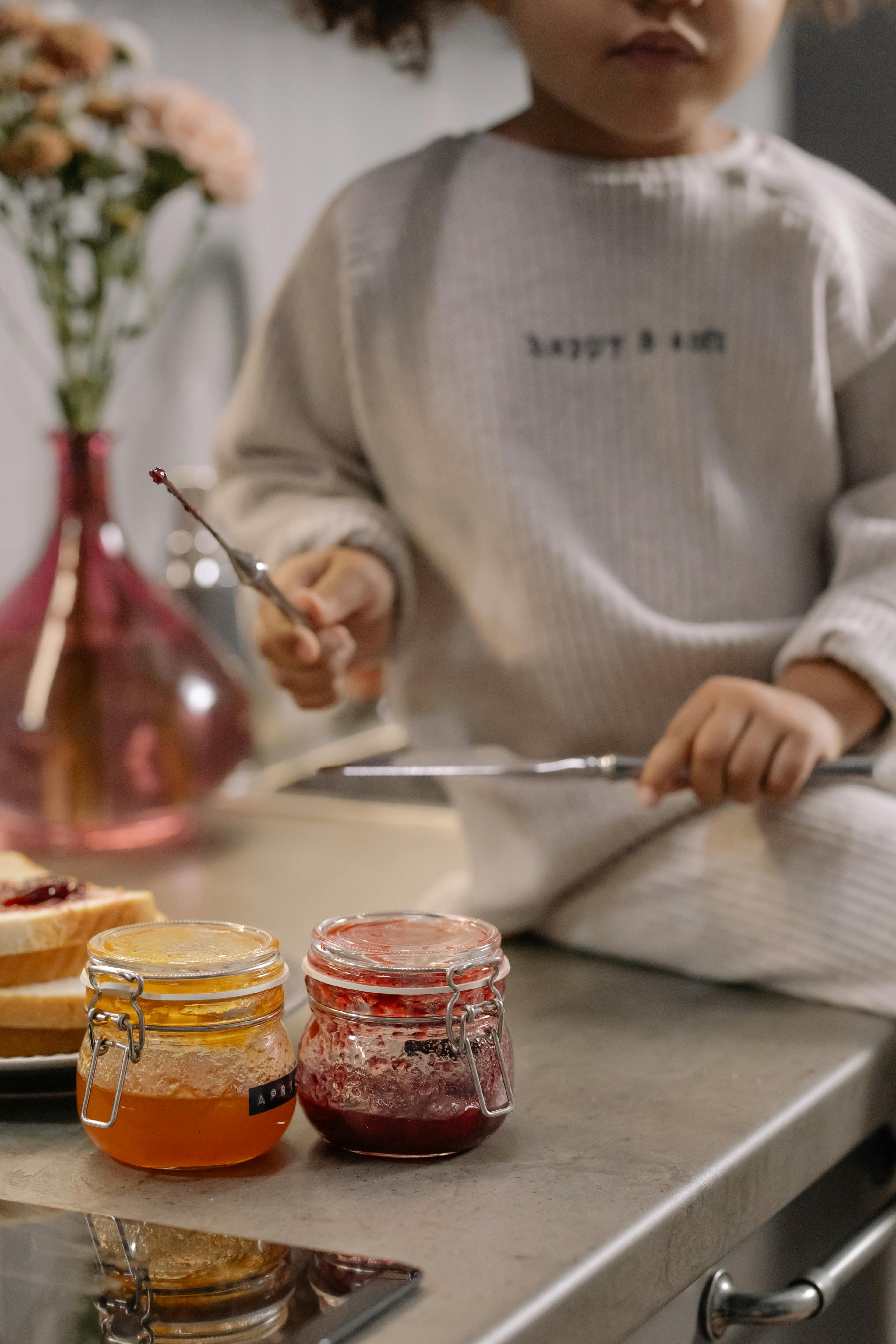 A Kid Sitting Near Jars with Jams · Free Stock Photo