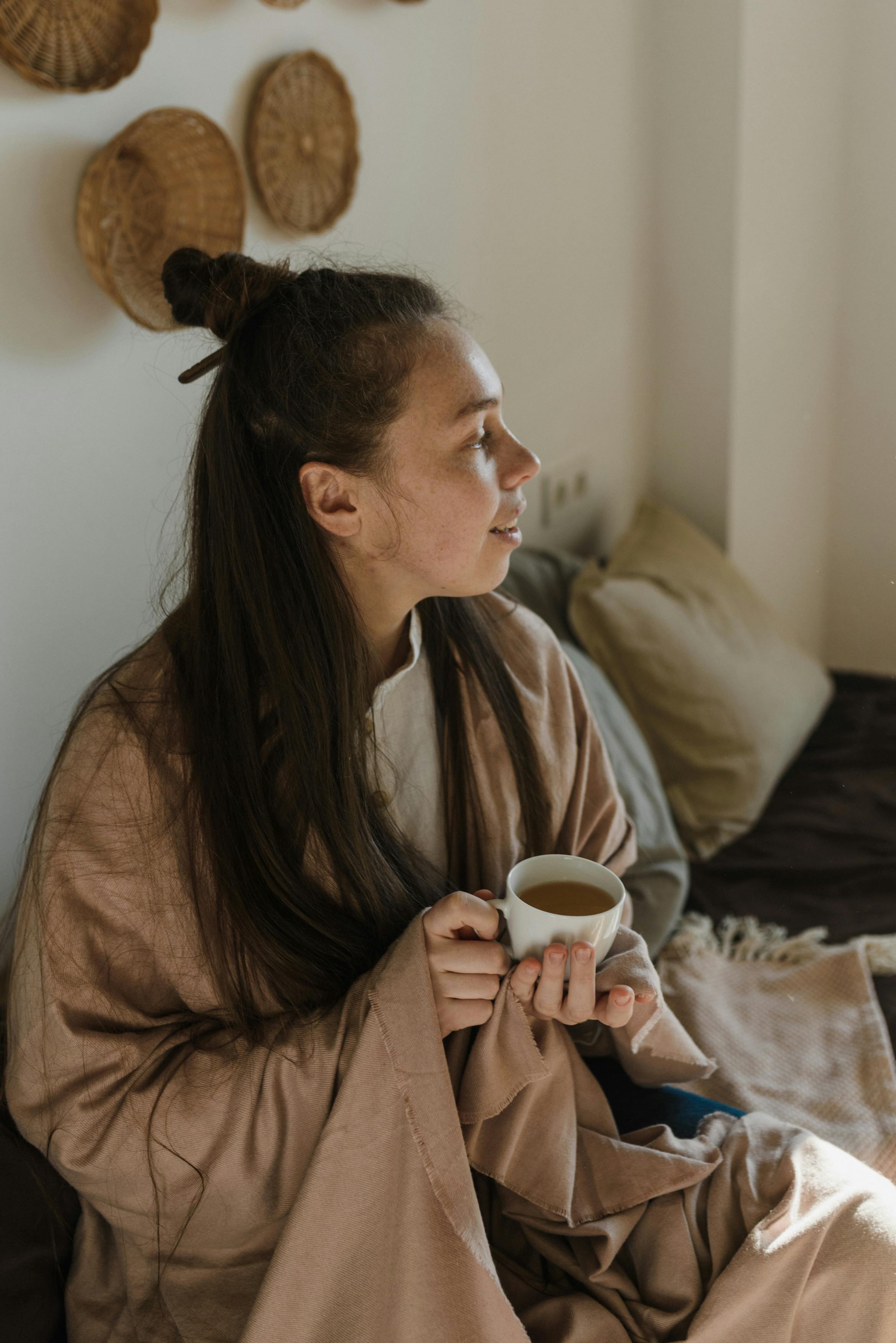 A Woman in Brown Robe Holding a Cup of Drink · Free Stock Photo