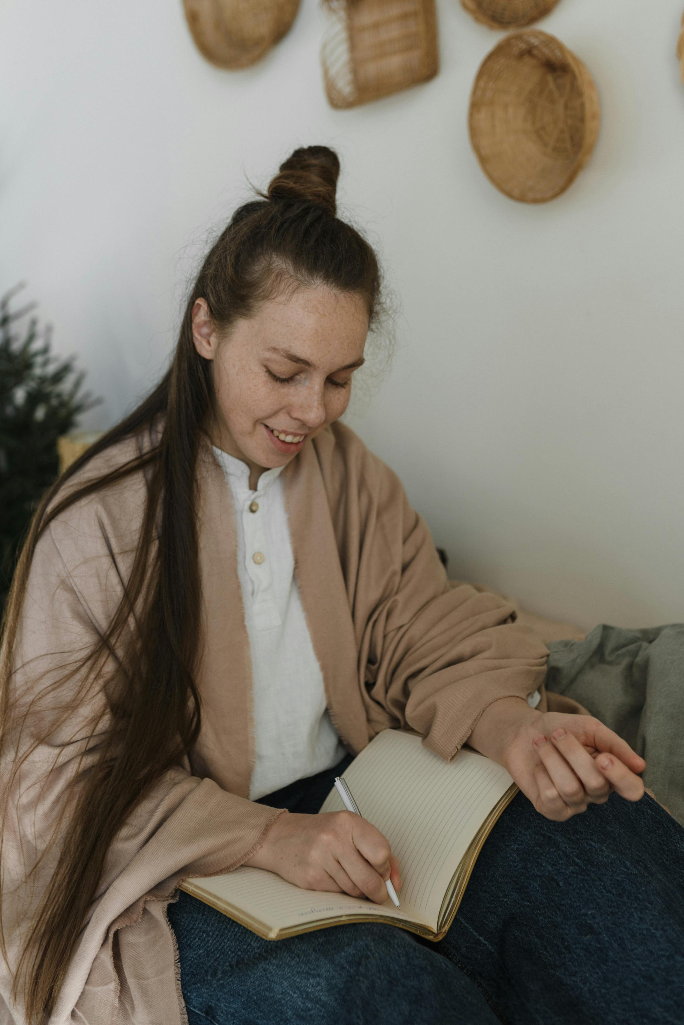 A Woman in Brown Robe Writing on a Notebook · Free Stock Photo