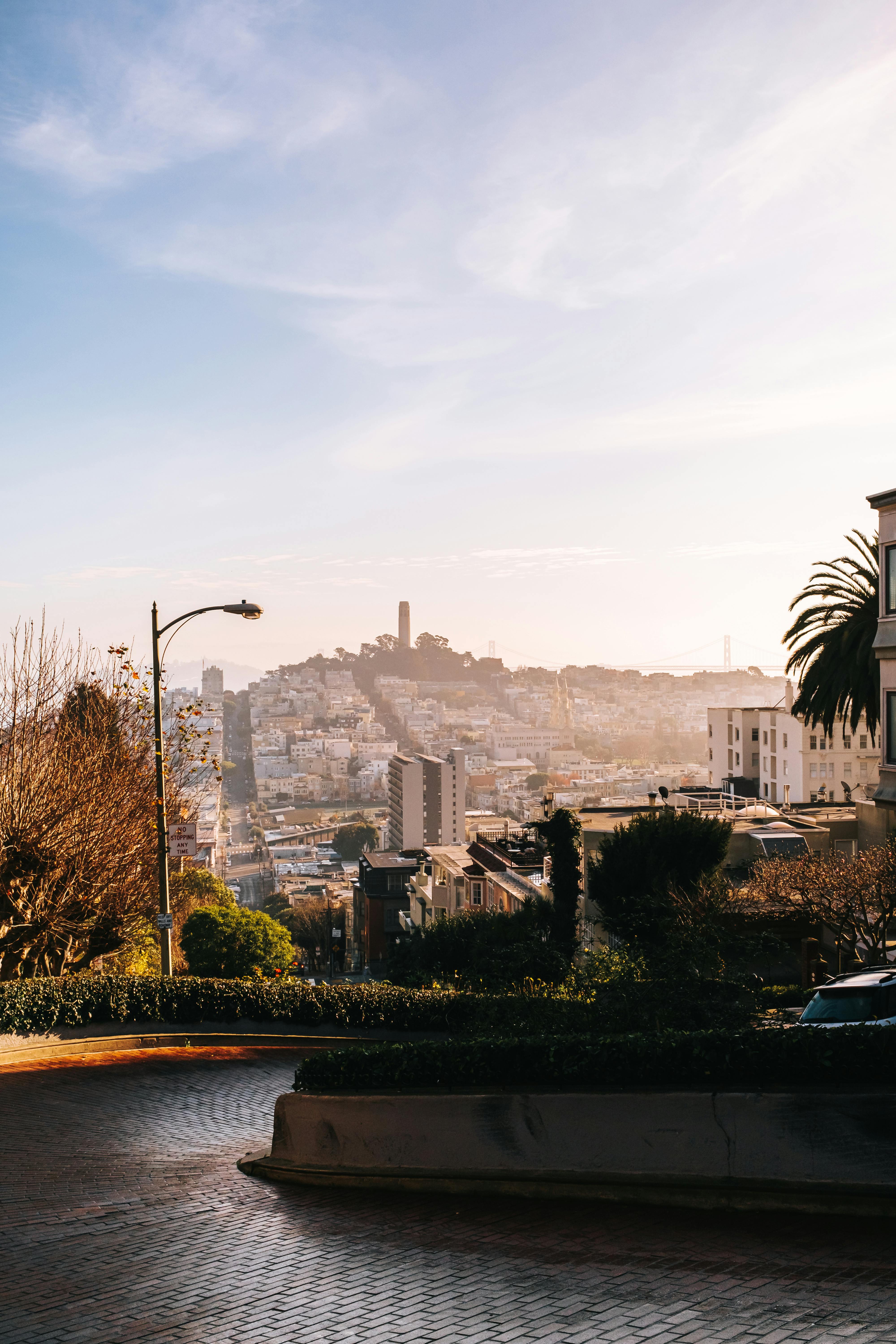 A Curved Inclined Road Near City Buildings Under White Sky · Free Stock ...