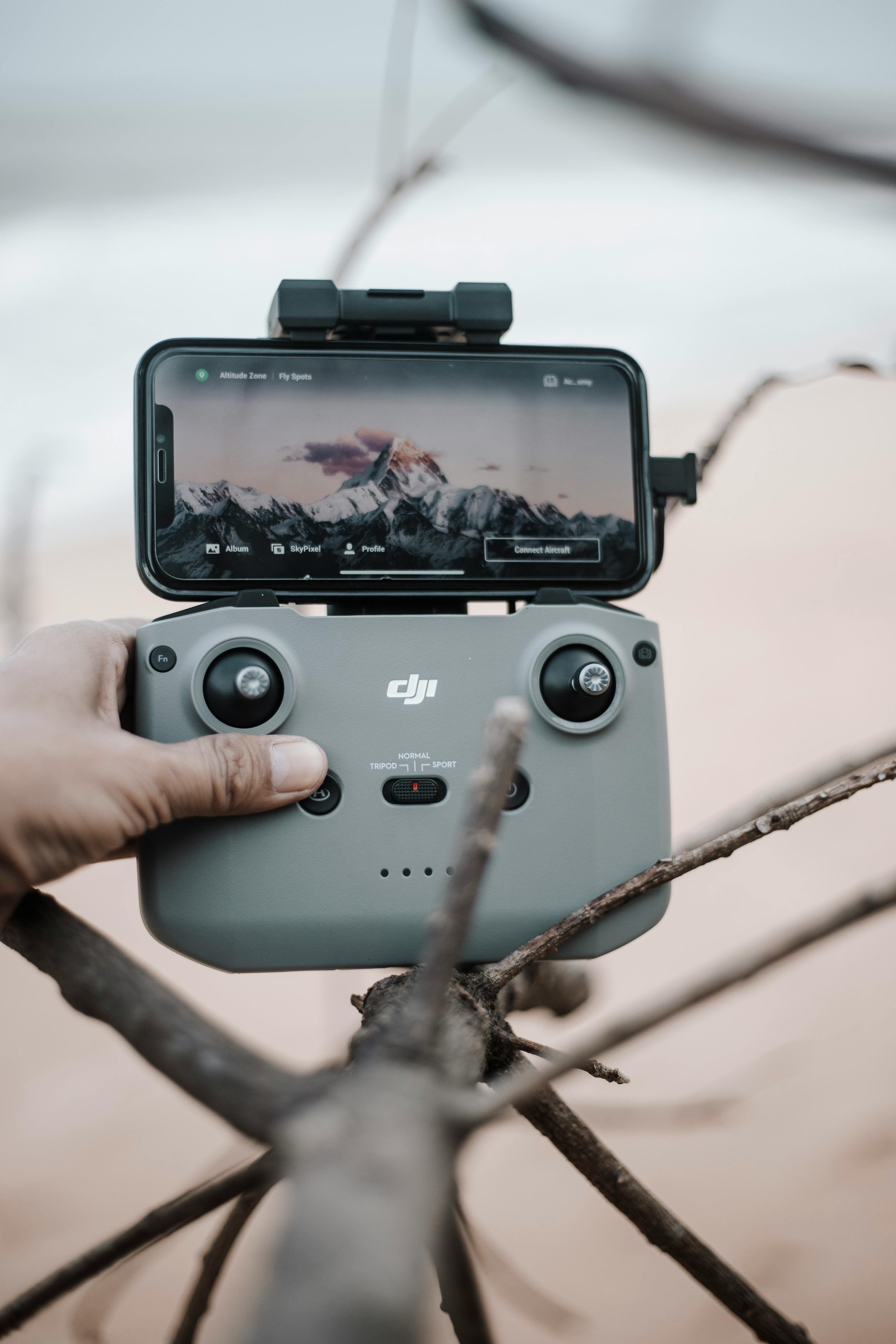 Crop anonymous man showing UAV controller with smartphone screen with ...