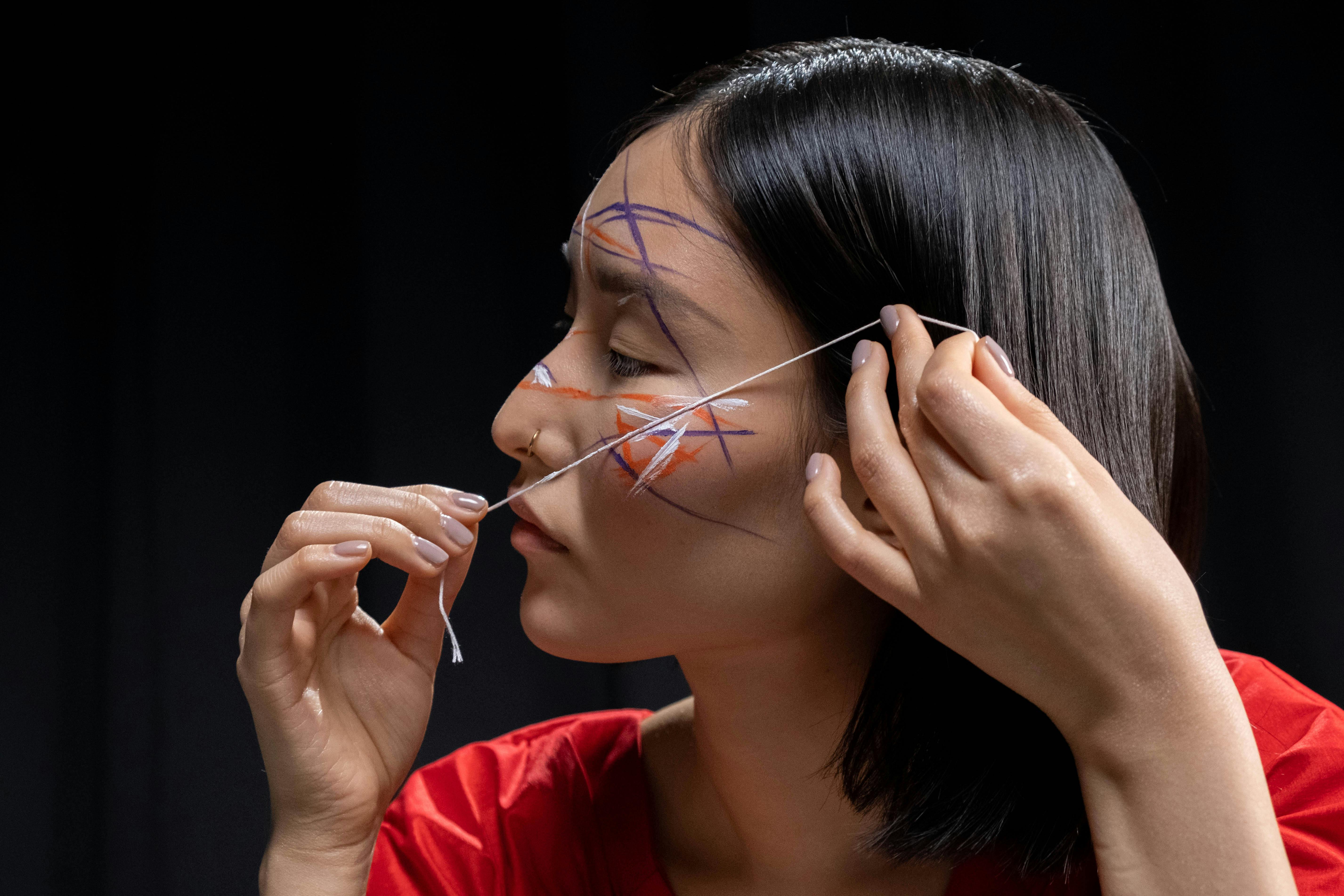 Woman in Red Shirt Applying Face Paint with a Thread · Free Stock Photo