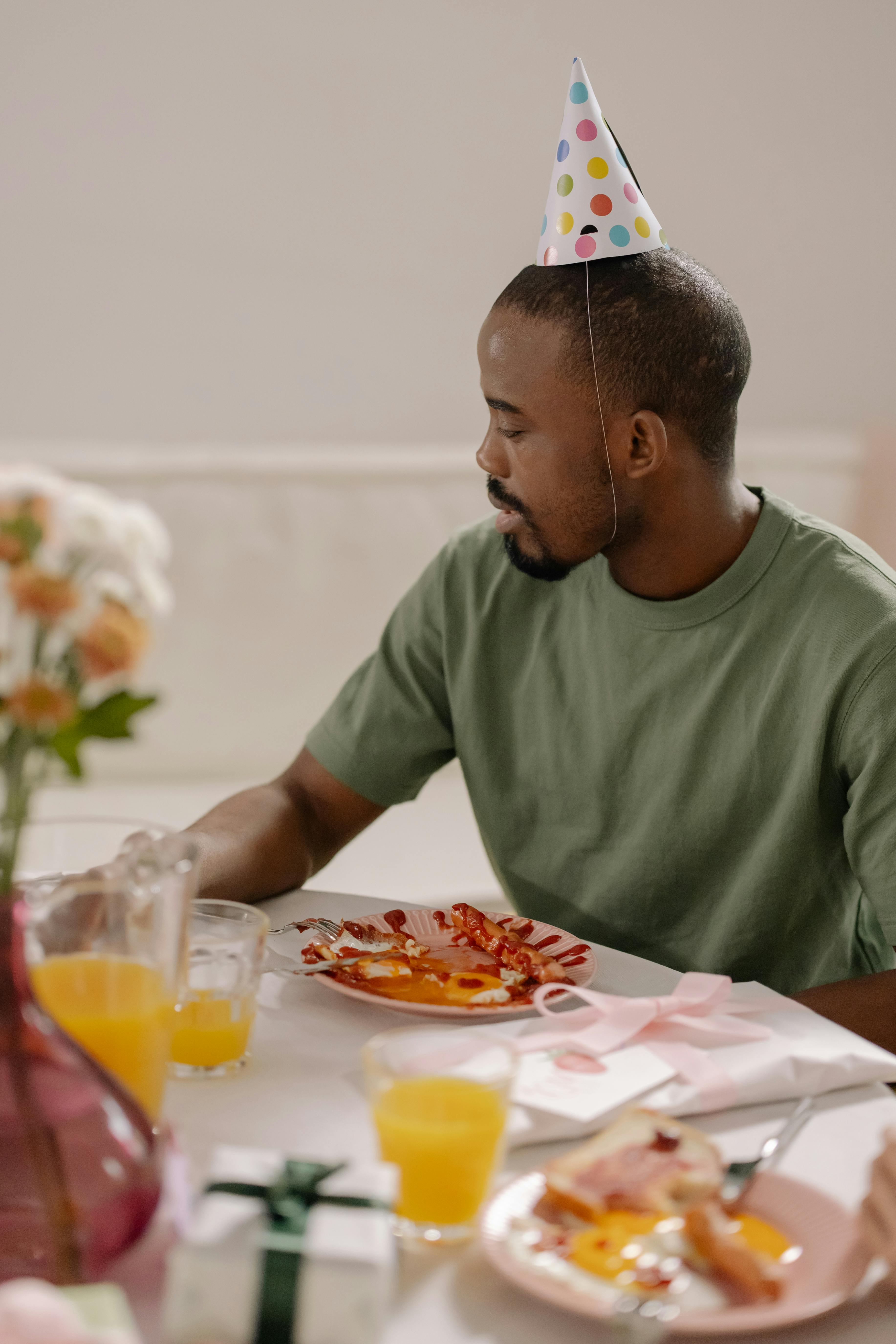 Man in Party Hat Sitting by Table · Free Stock Photo