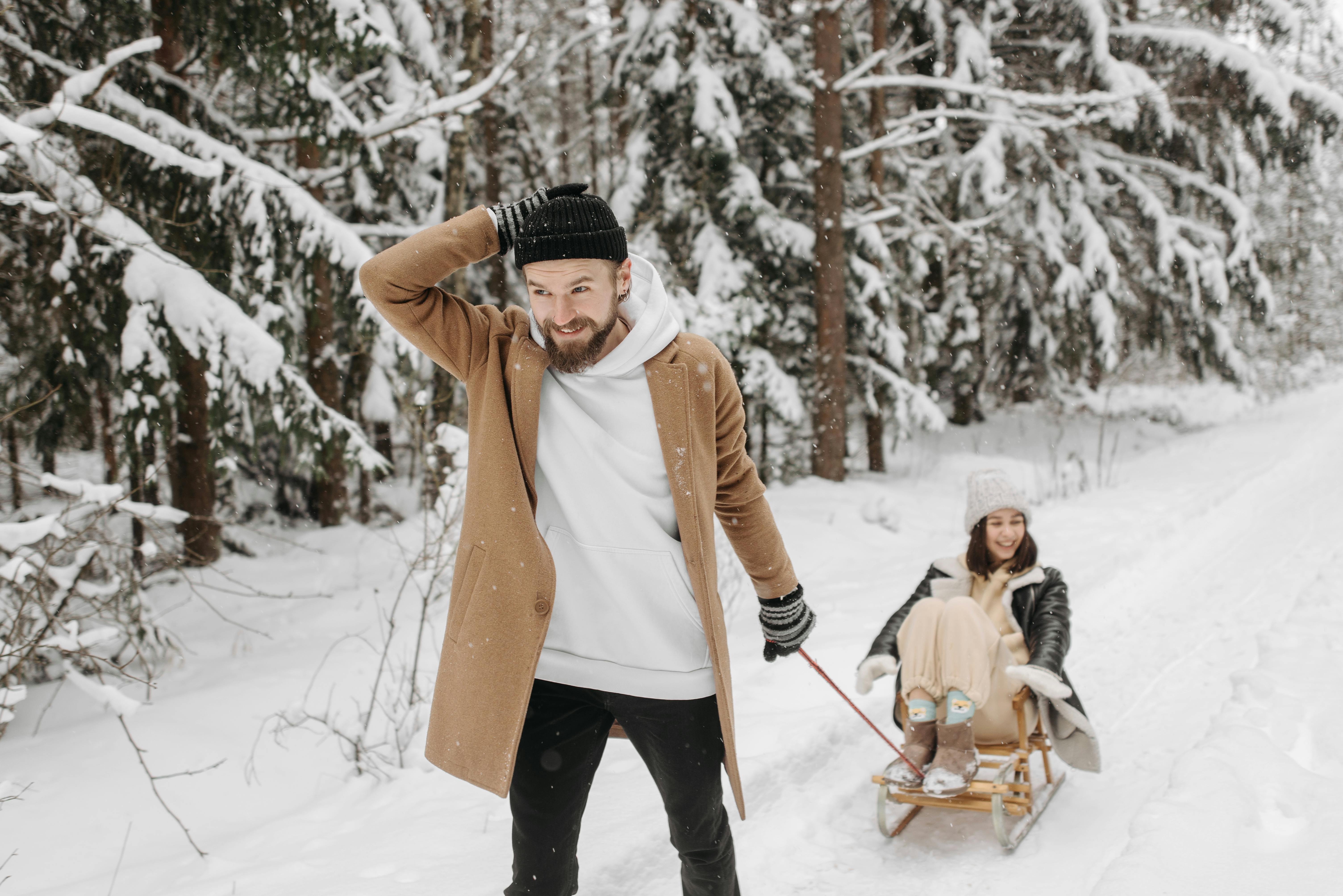 A Man Pushing a Woman on a Sleigh · Free Stock Photo