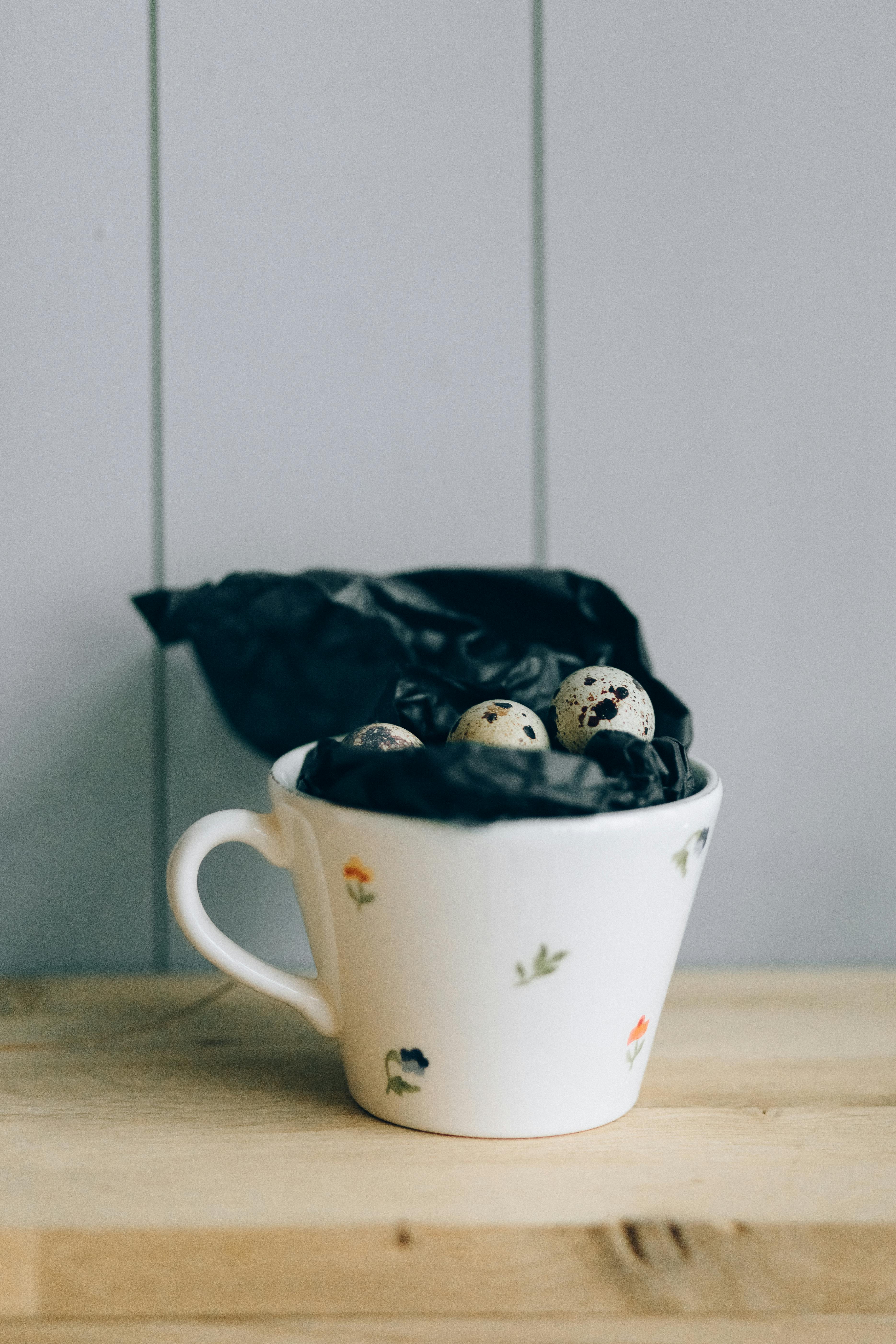 Quail Eggs on Black Material in a Tea Cup · Free Stock Photo