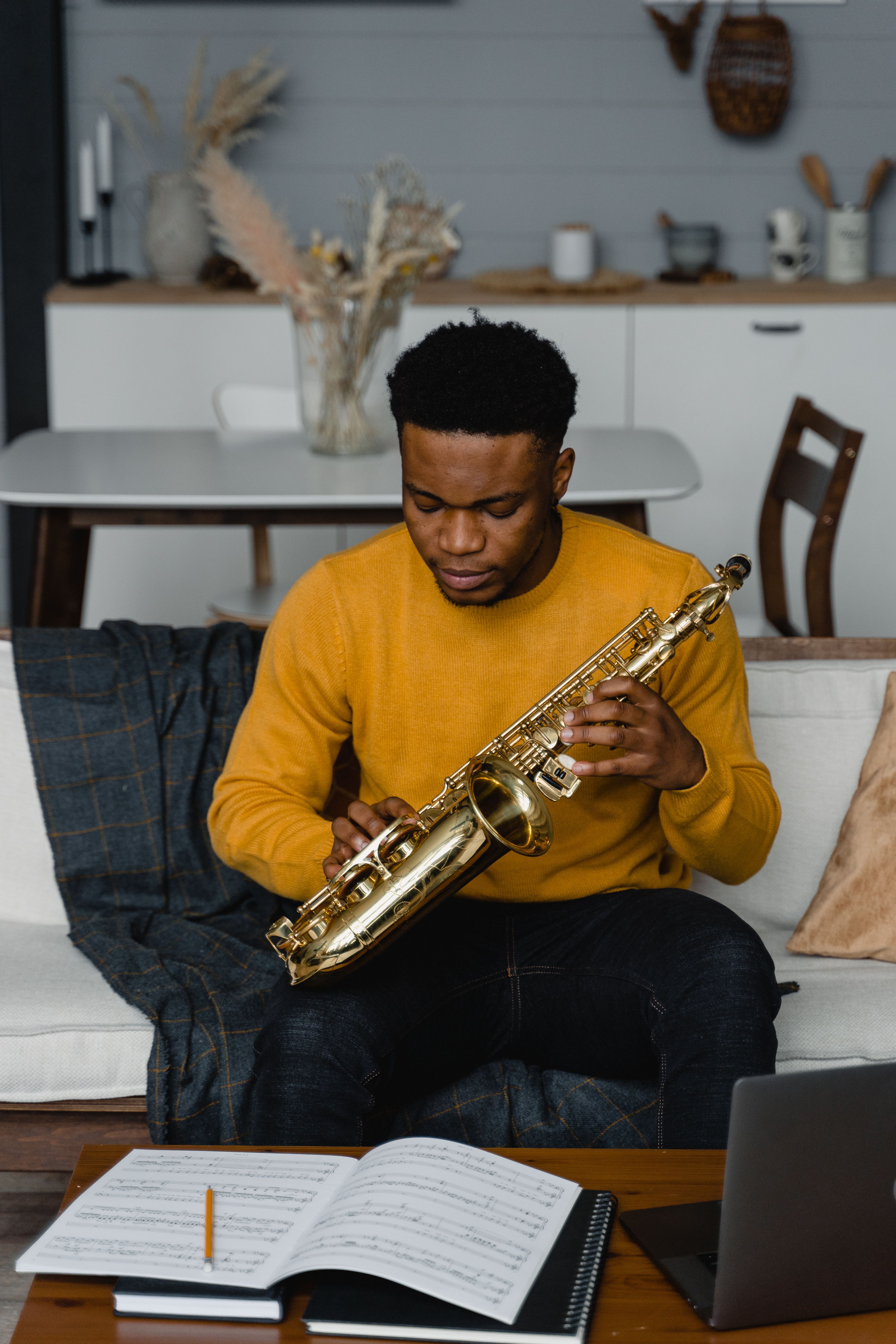 A Man Holding a Saxophone While Sitting · Free Stock Photo