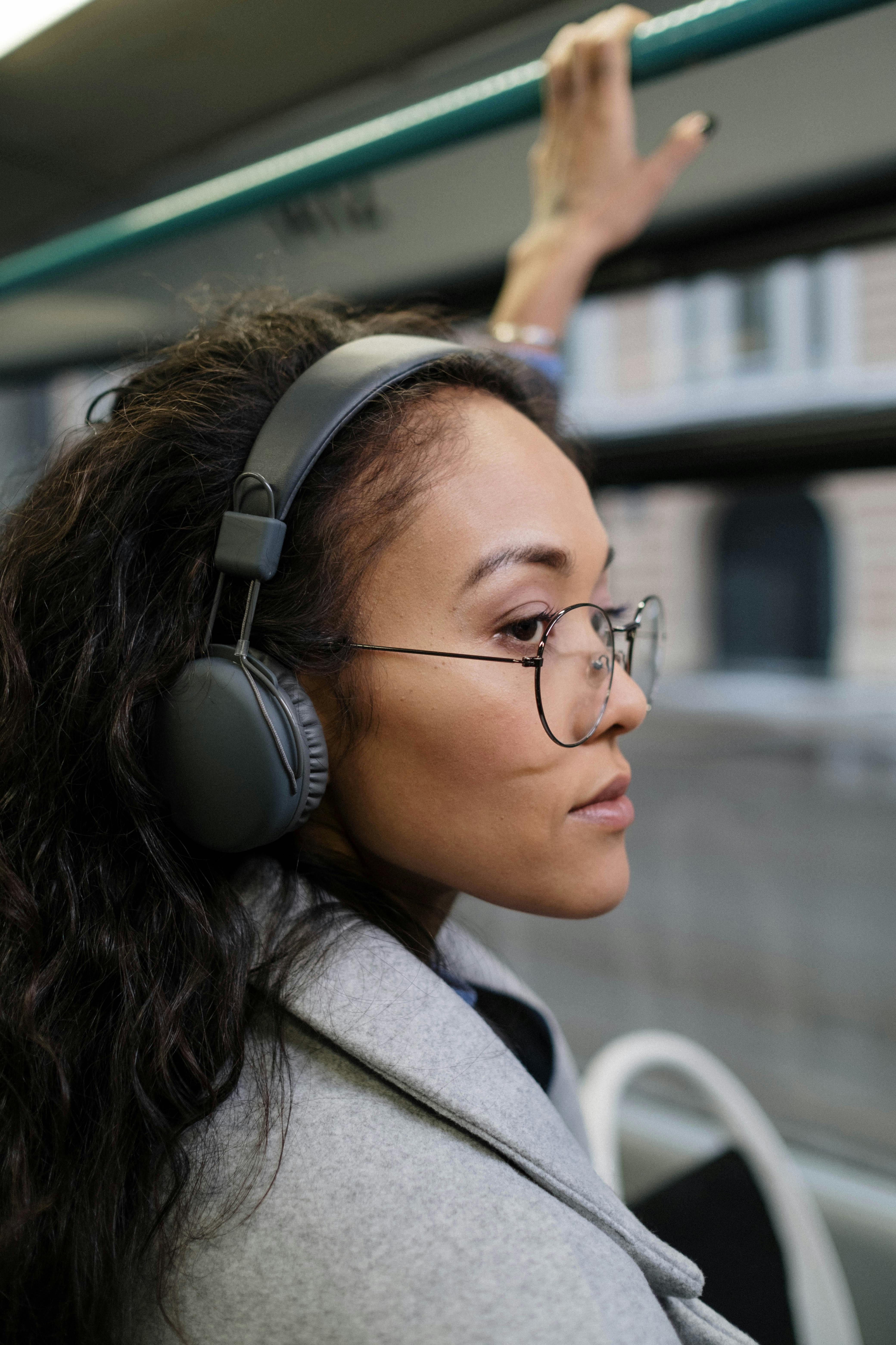 A Woman Wearing Headphones While Holding to a Steel Handle · Free Stock ...