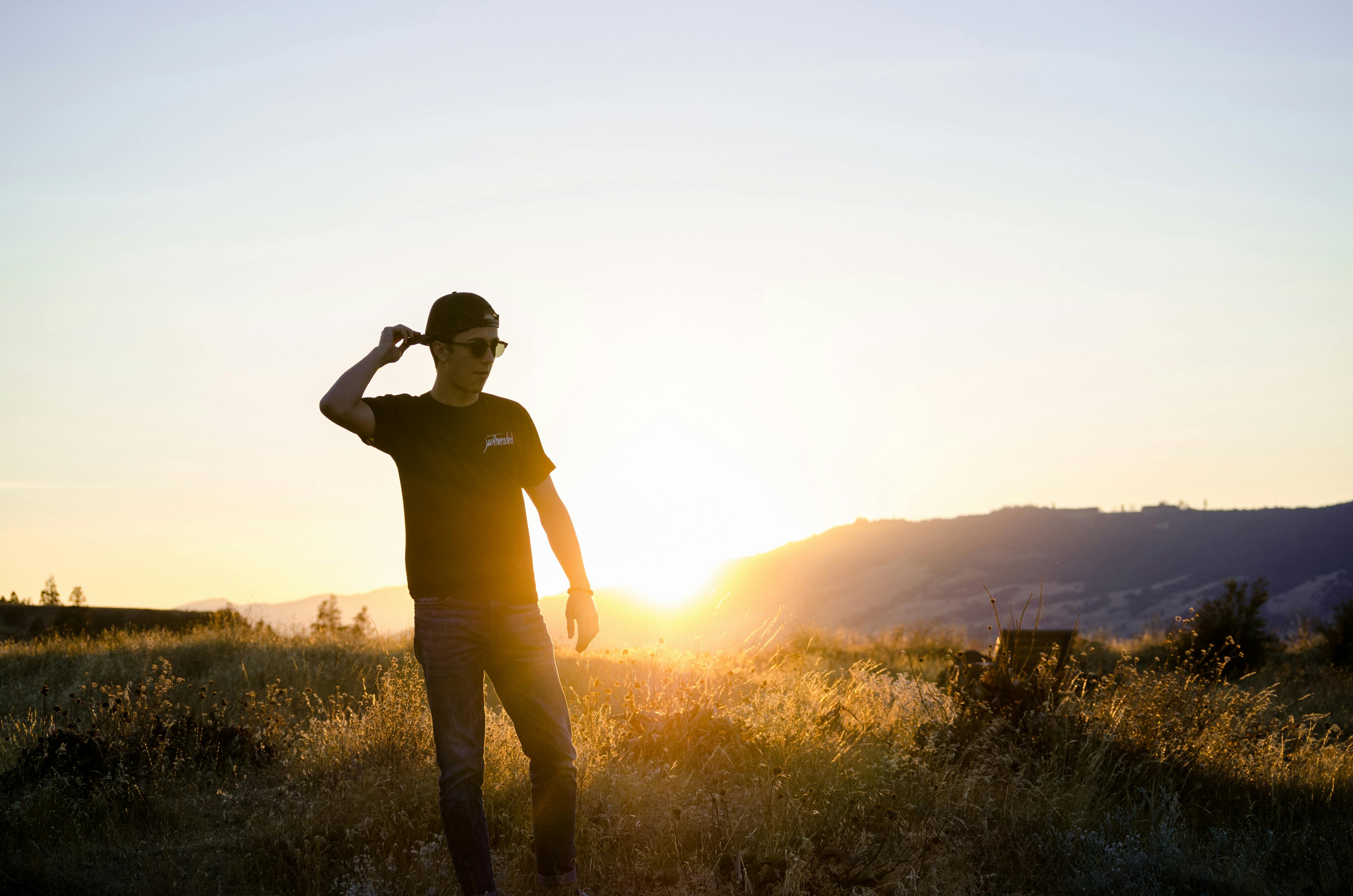 Man Standing on Grass Field Overlooking Sunrise · Free Stock Photo