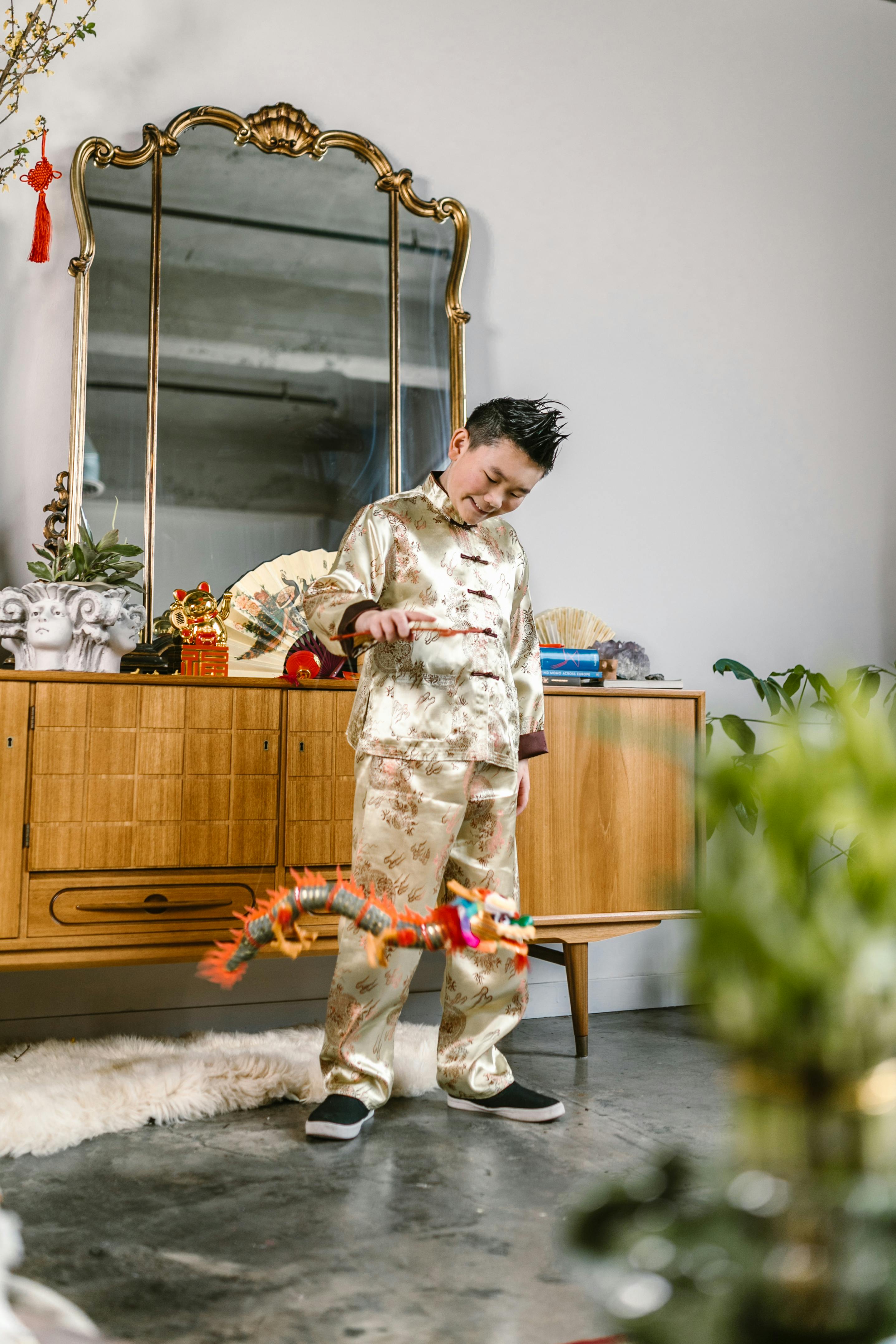A Boy in Traditional Wear Playing with a Dragon Puppet · Free Stock Photo