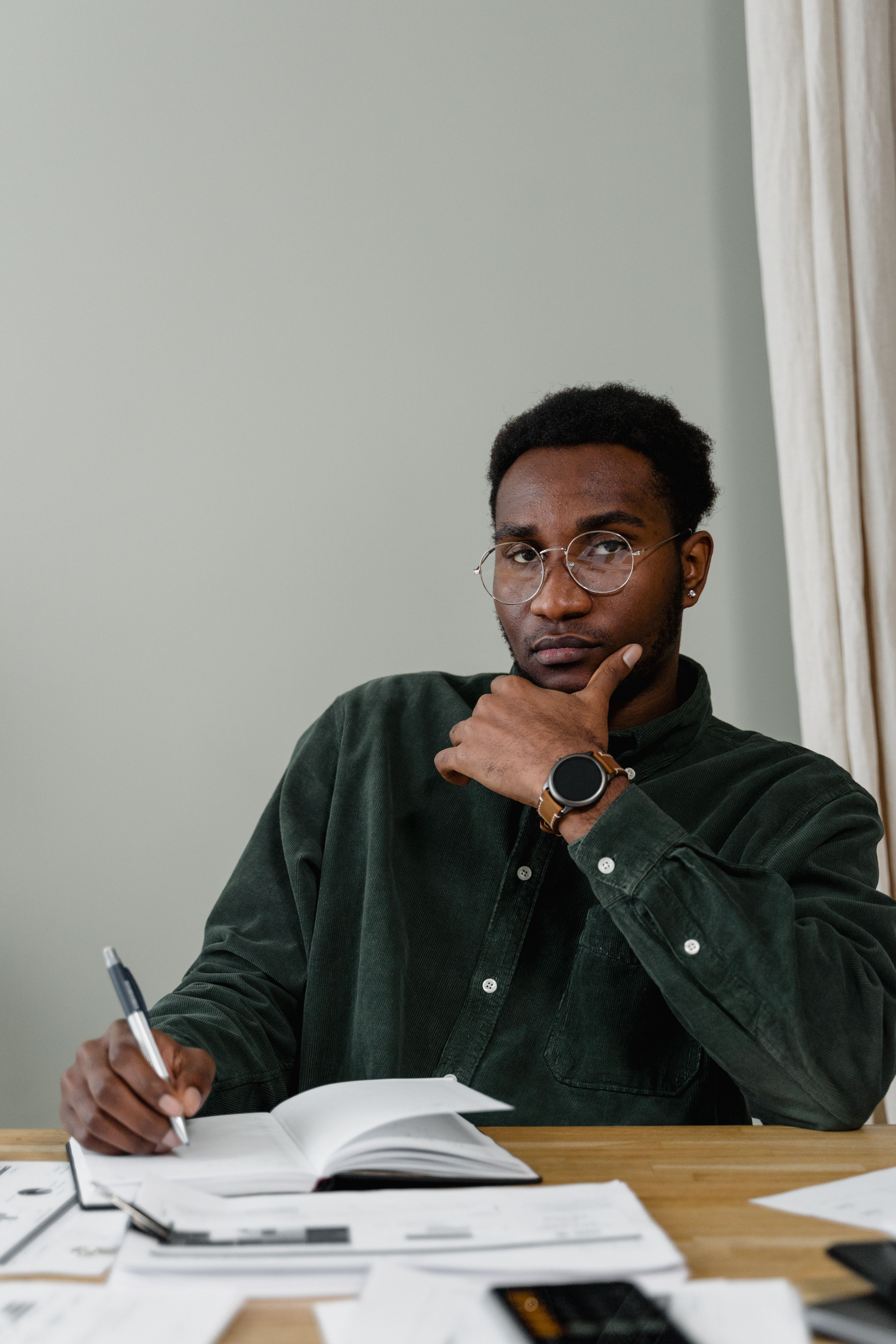 Man Sitting while Holding a Pen and Notebook · Free Stock Photo