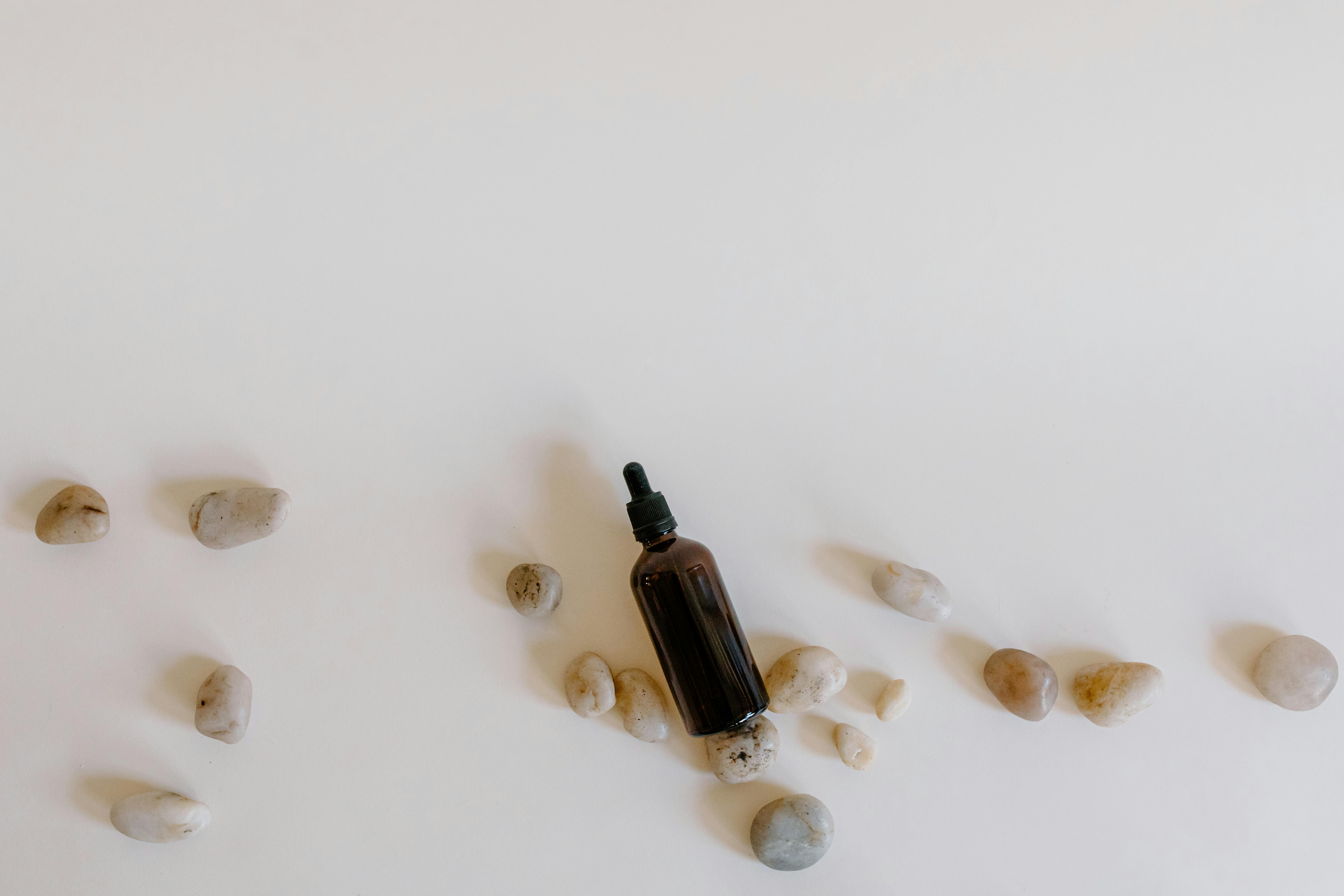 Essential Oil with Stones on White Surface · Free Stock Photo