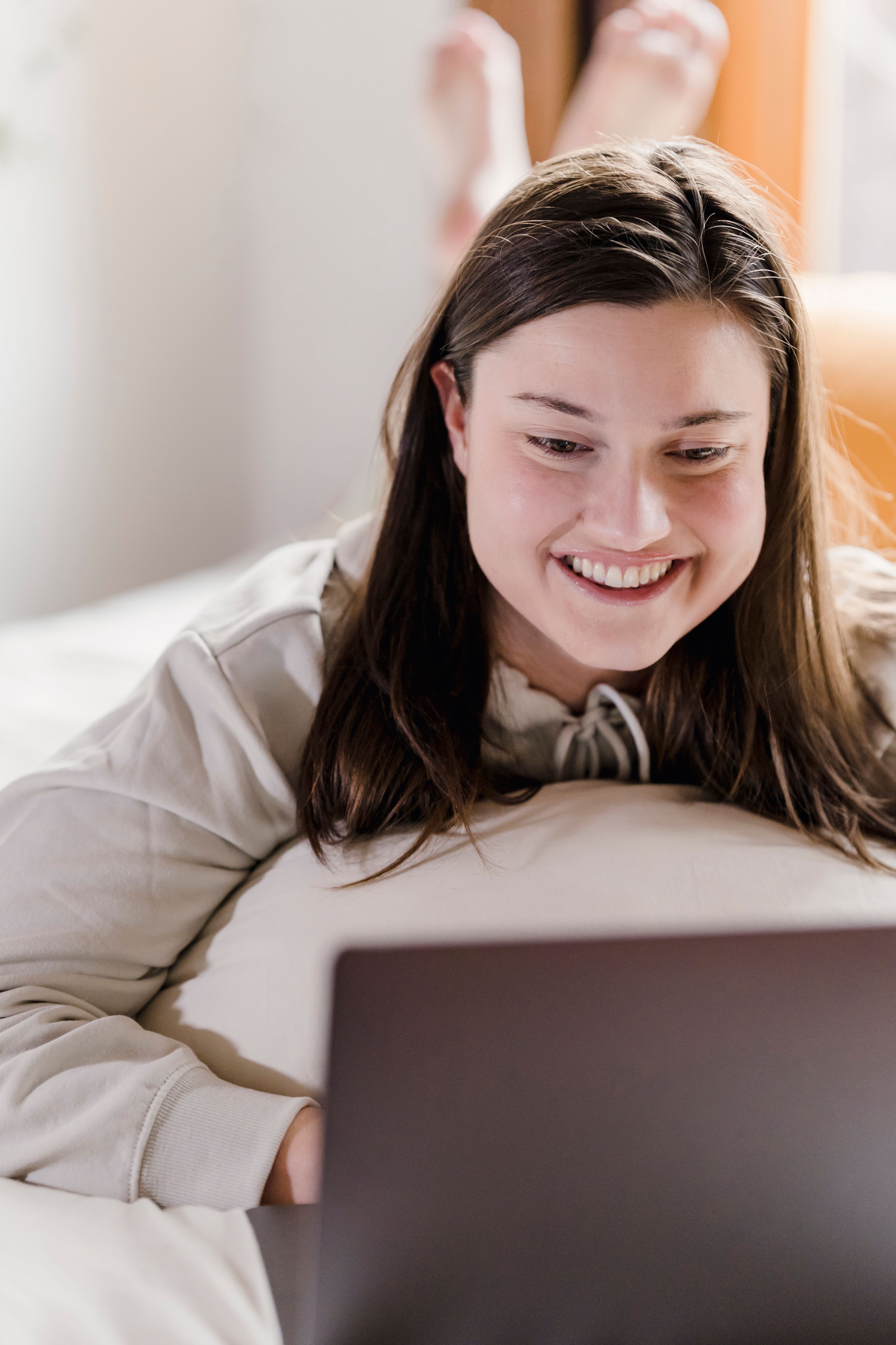 Smiling woman browsing laptop in bedroom · Free Stock Photo