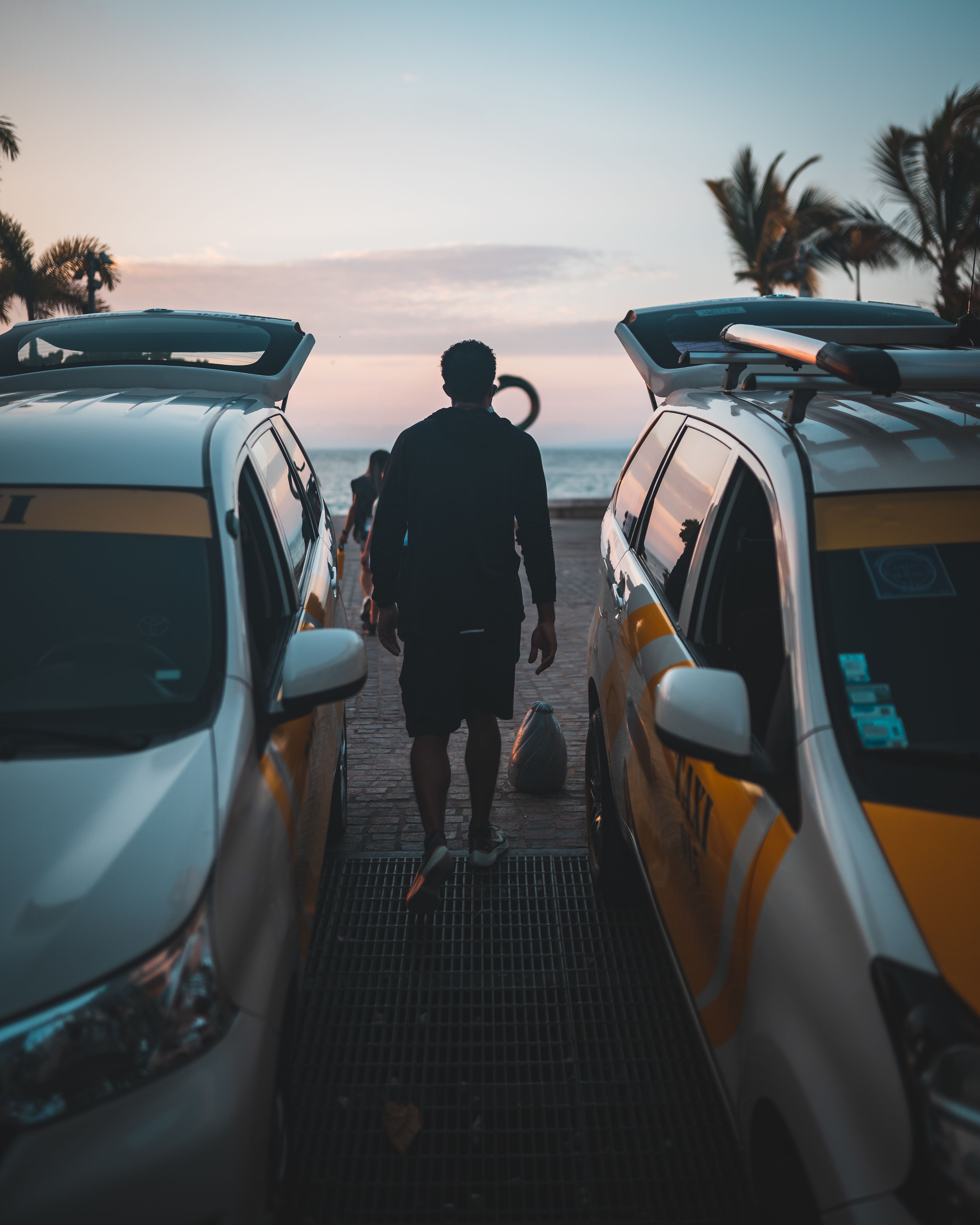 A Man in Shorts Walking between Cars · Free Stock Photo