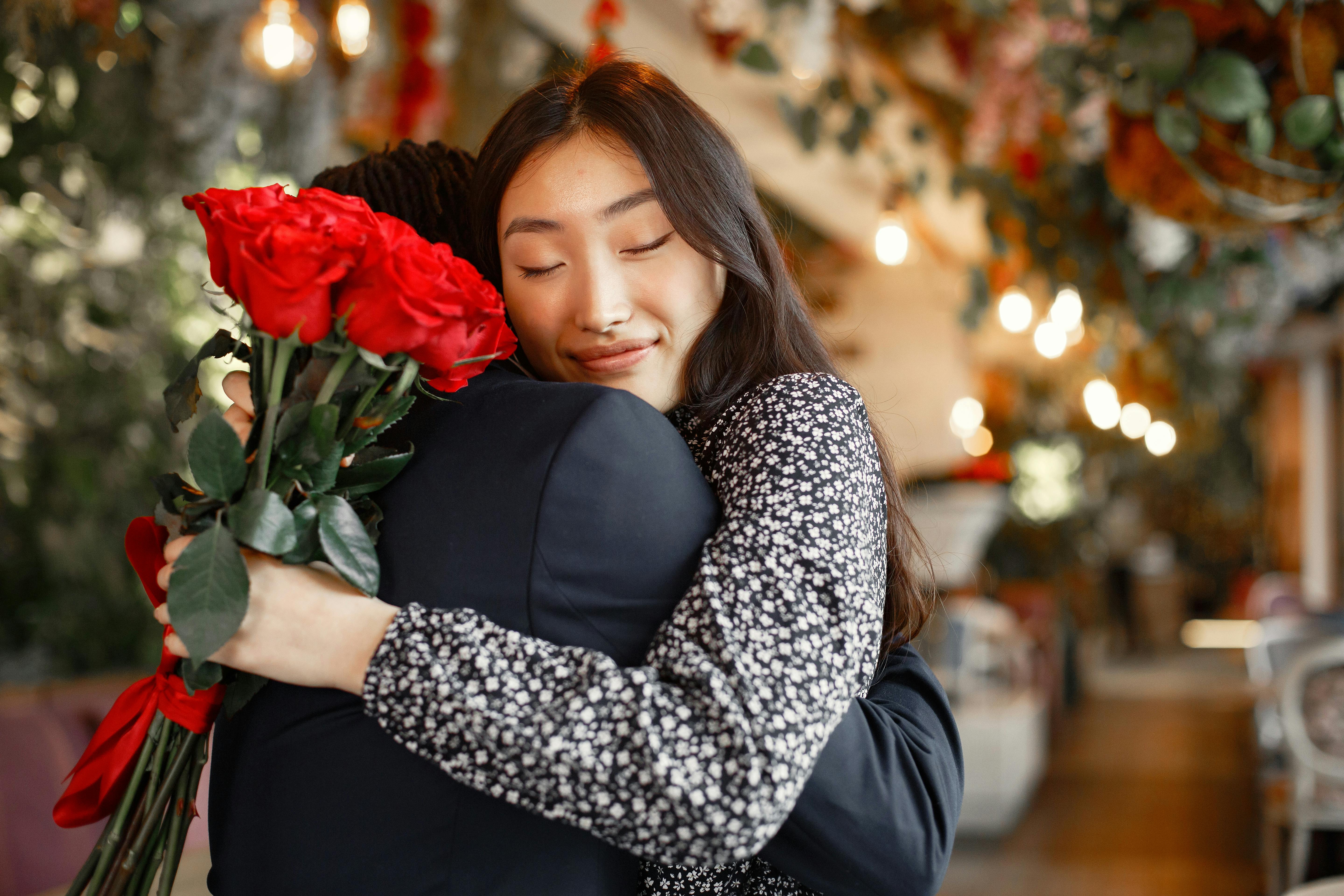 Woman Holding Bouquet of Red Roses Embracing Man · Free Stock Photo
