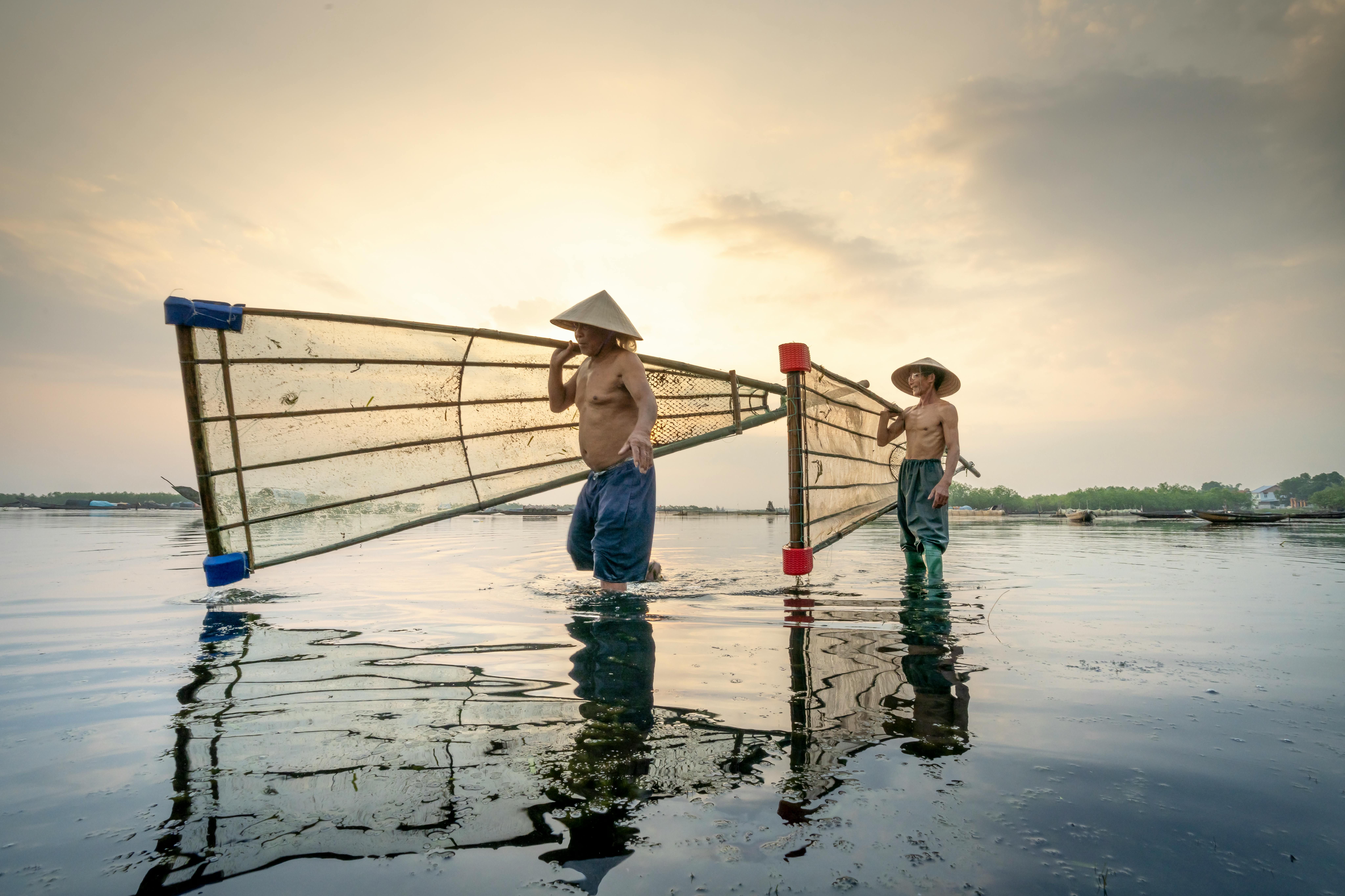 Fishermen in Vietnamese hats in water with fishing tools · Free Stock Photo