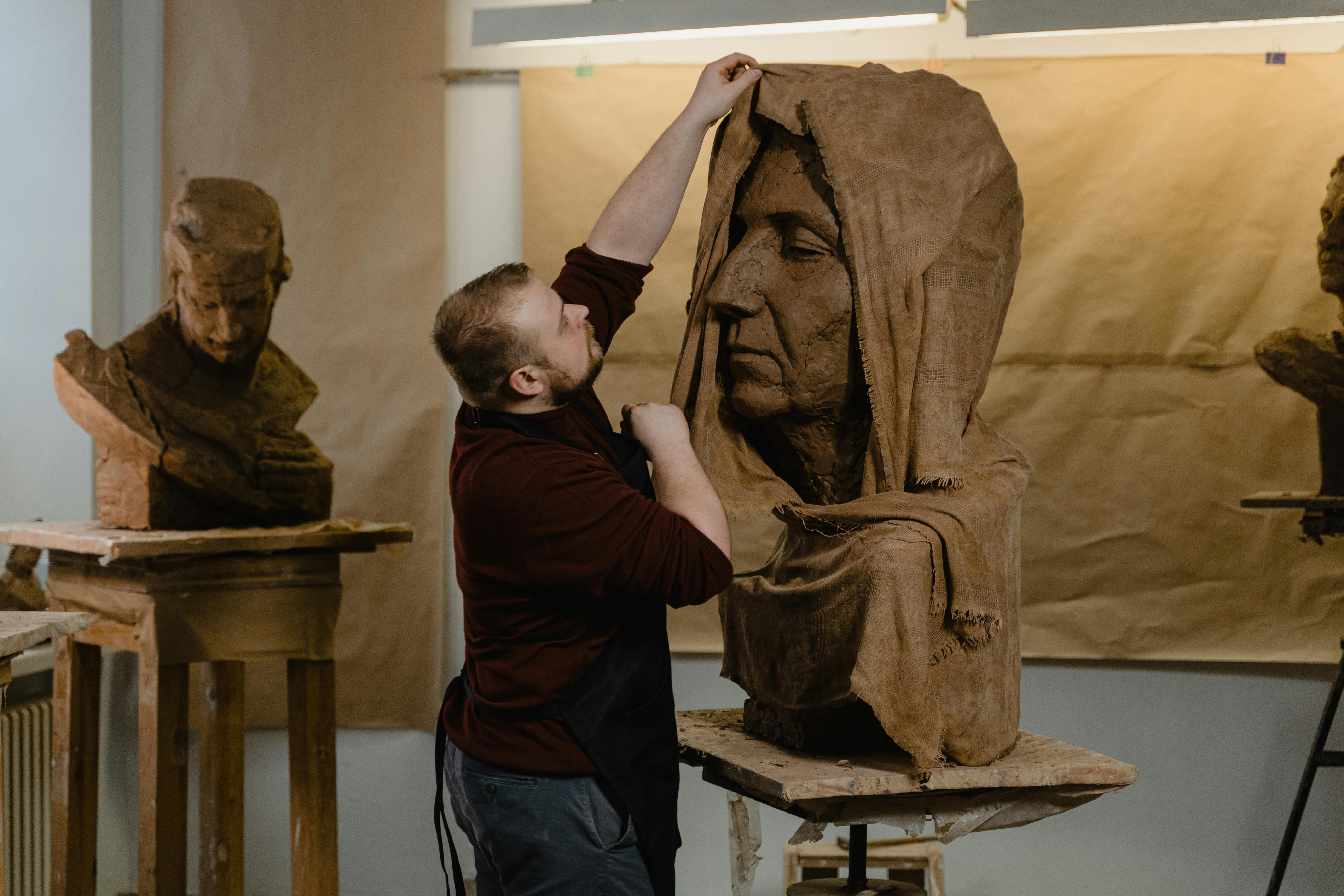 A Sculptor Putting a Cloth on a Clay Sculpture · Free Stock Photo