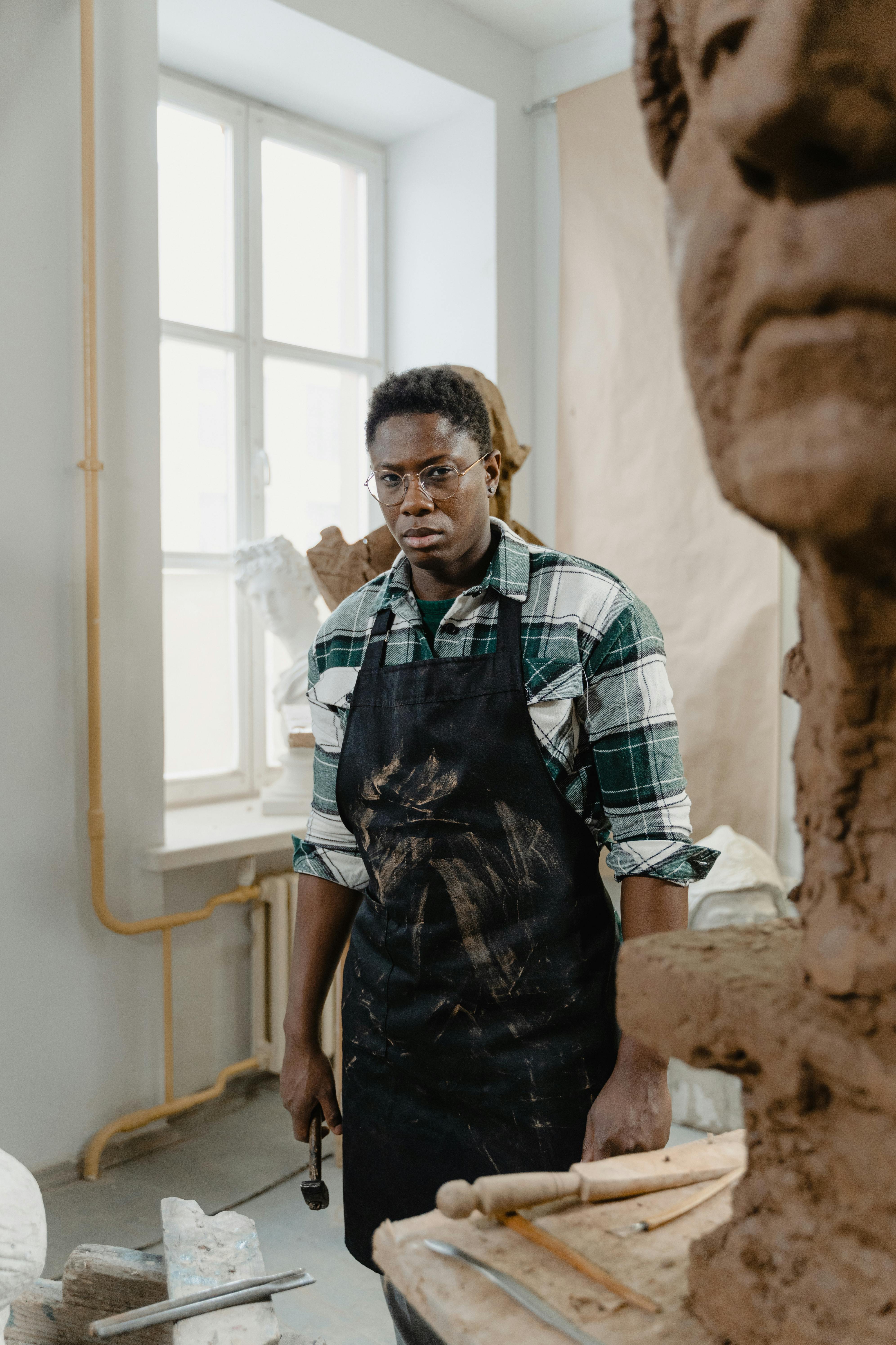 A Sculptor Wearing Plaid Shirt and Black Apron · Free Stock Photo