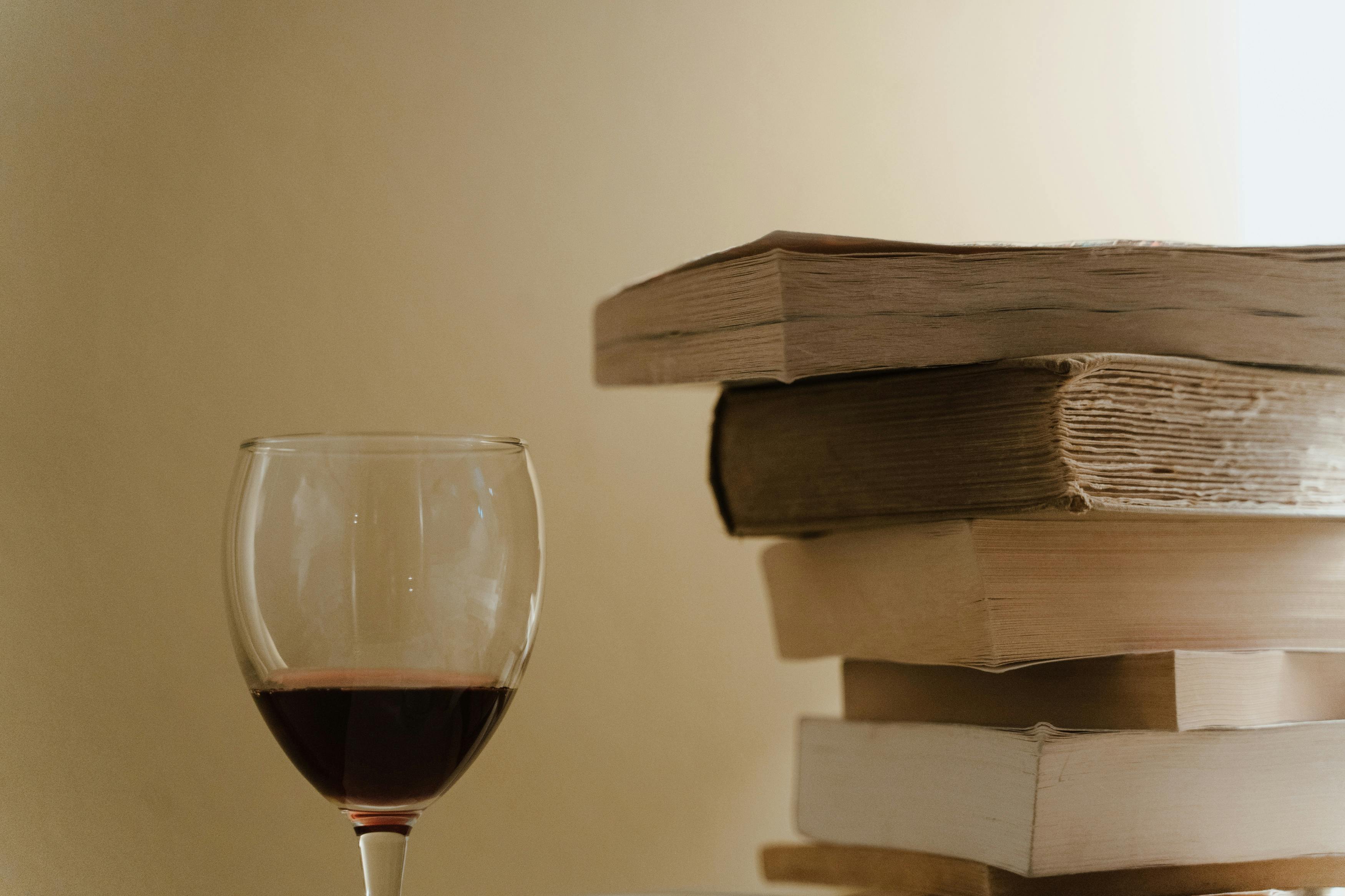 Glass of Red Wine Beside a Stack of Books · Free Stock Photo