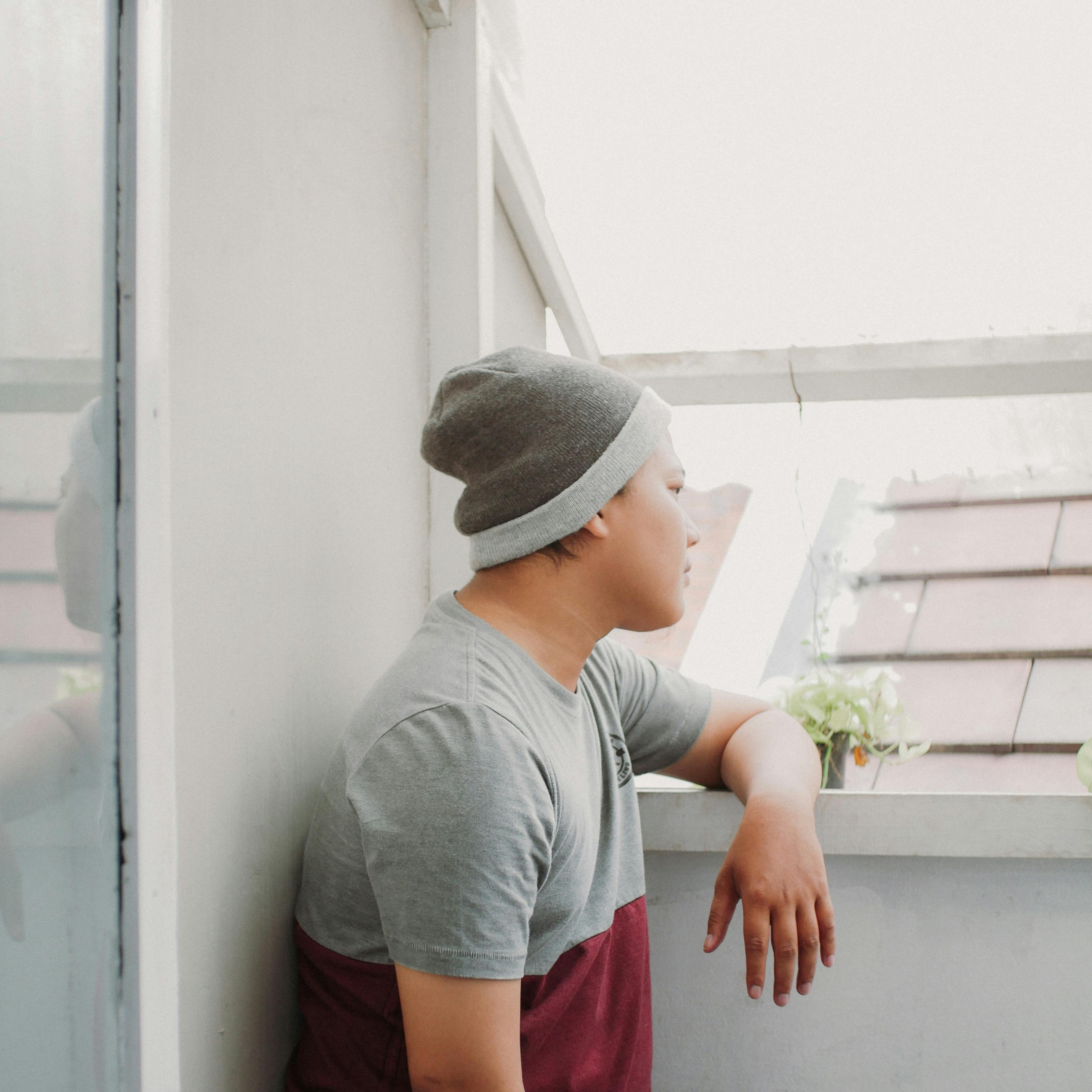 Man in Hat Looking out Window · Free Stock Photo