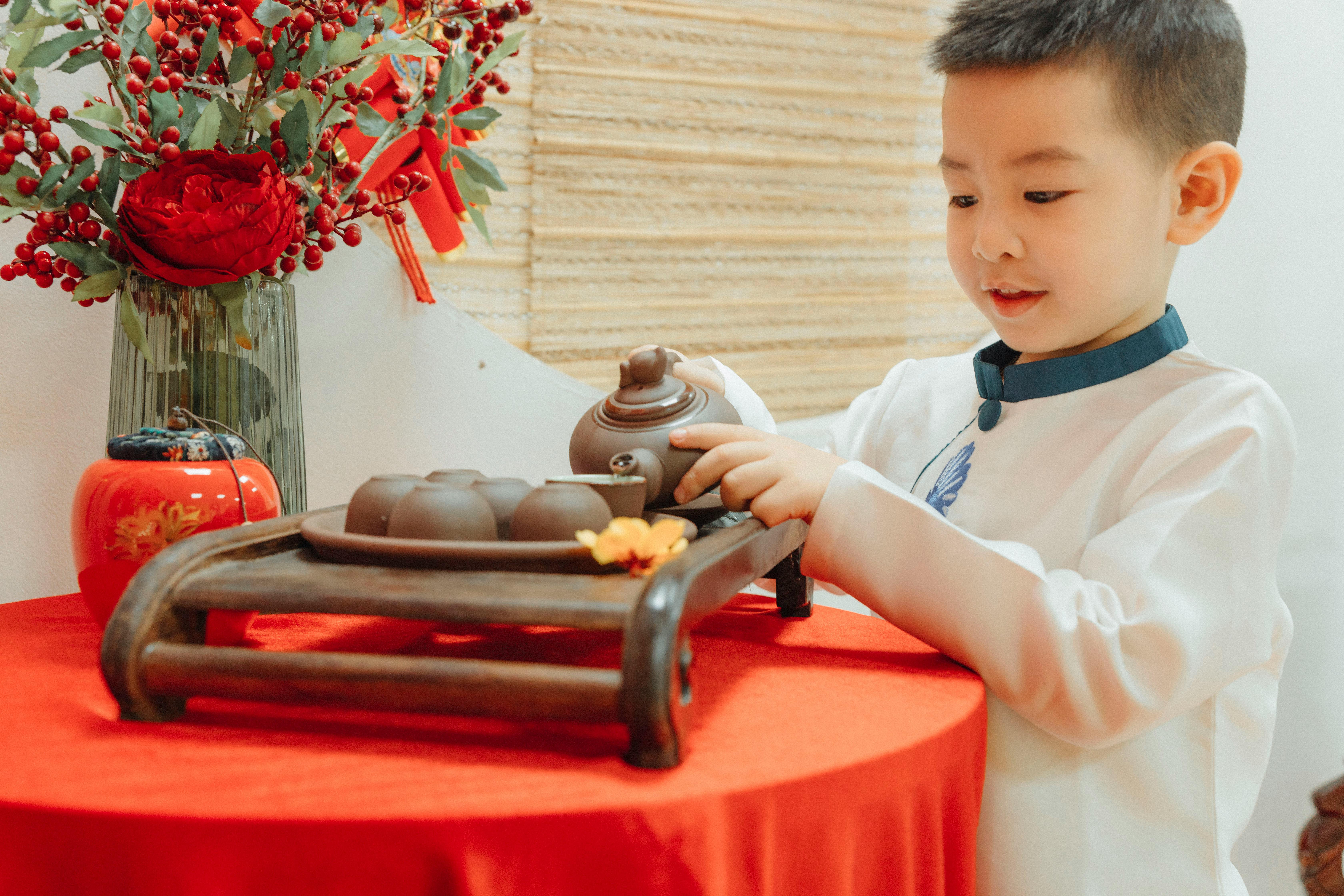 A Boy Pouring Tea on a Teacup · Free Stock Photo