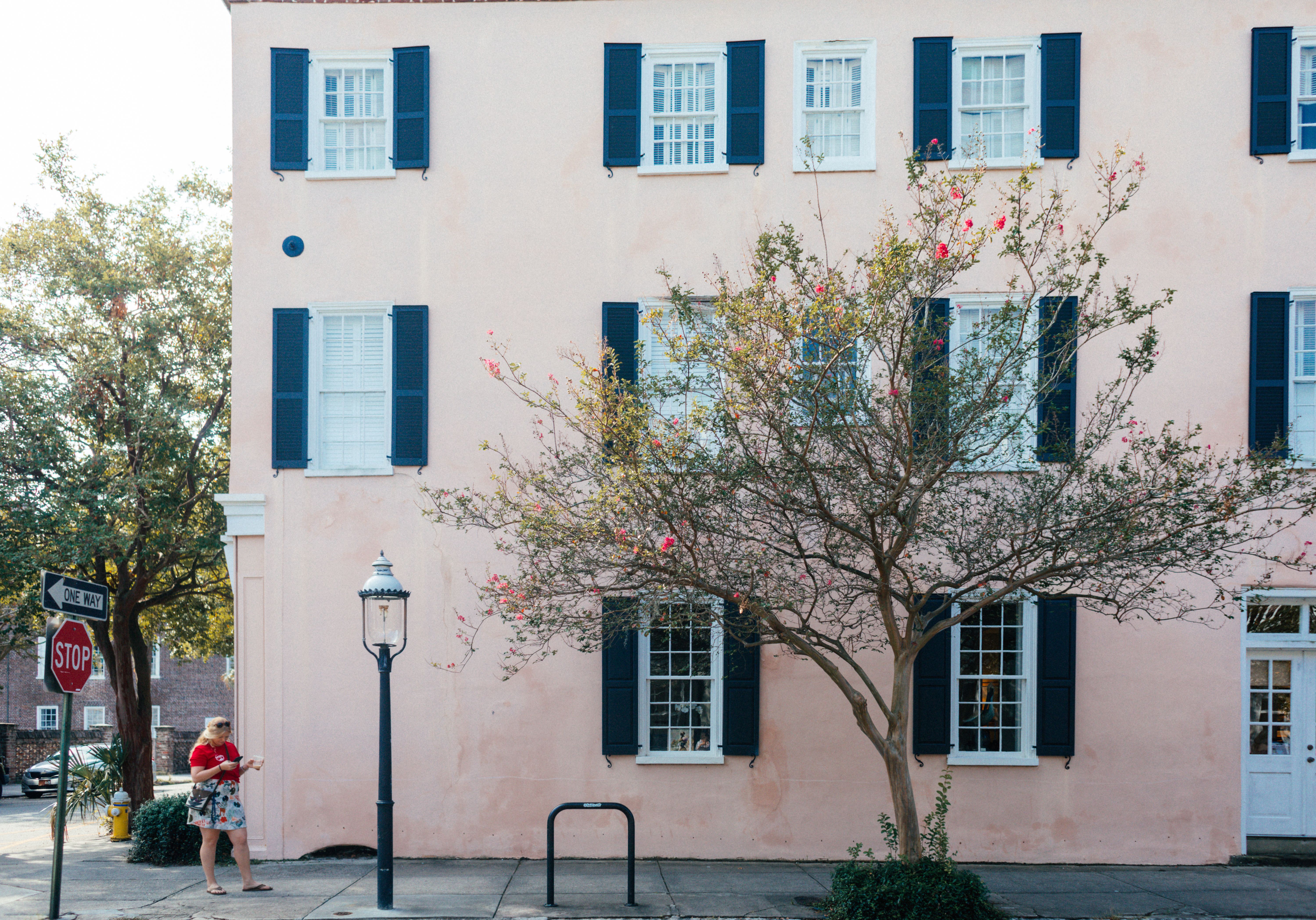 A Woman Walking on the Side of the Street Beside an Apartment Building ...