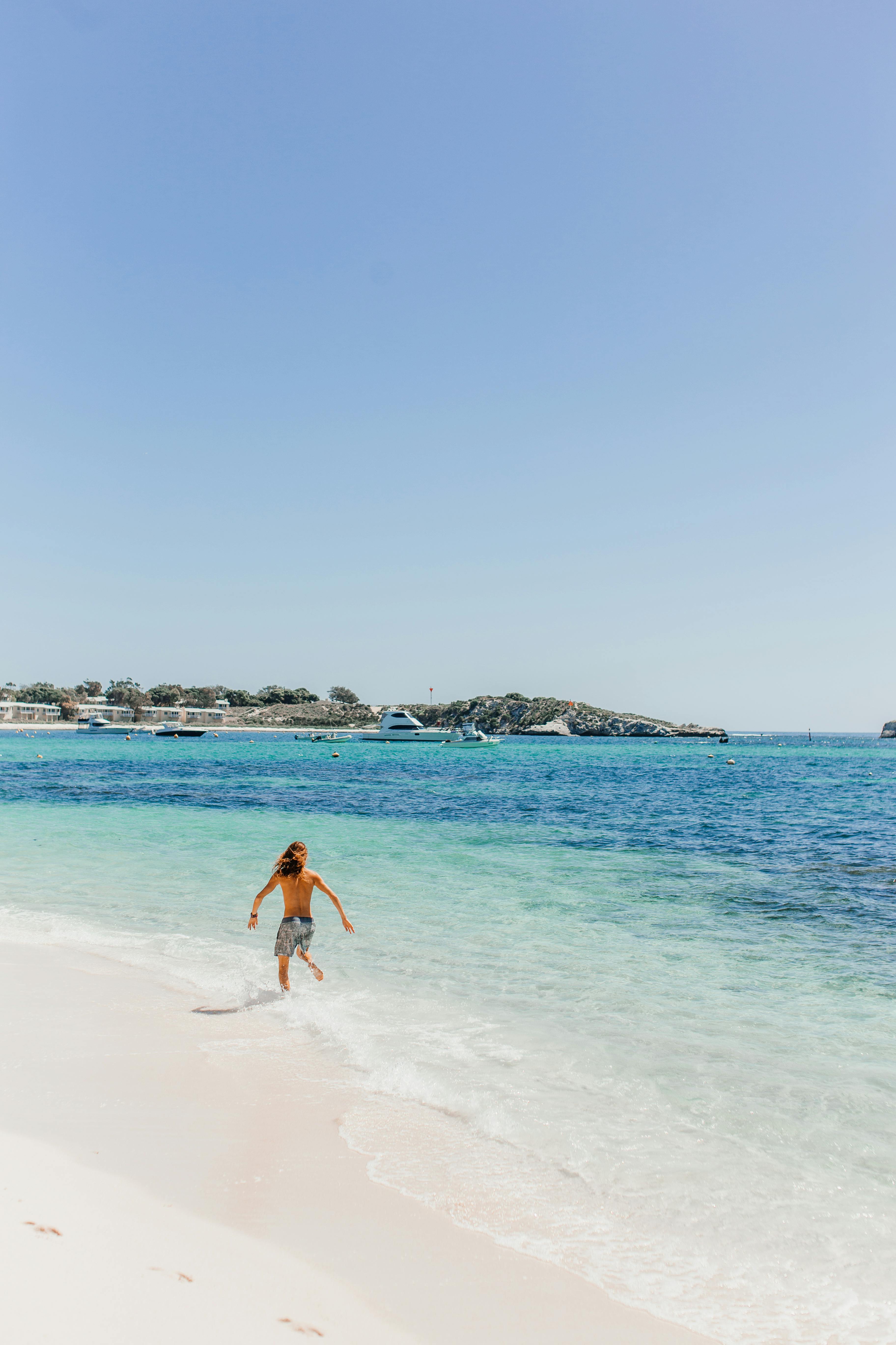 Man Running Along a Beach Ankle Deep in Water · Free Stock Photo