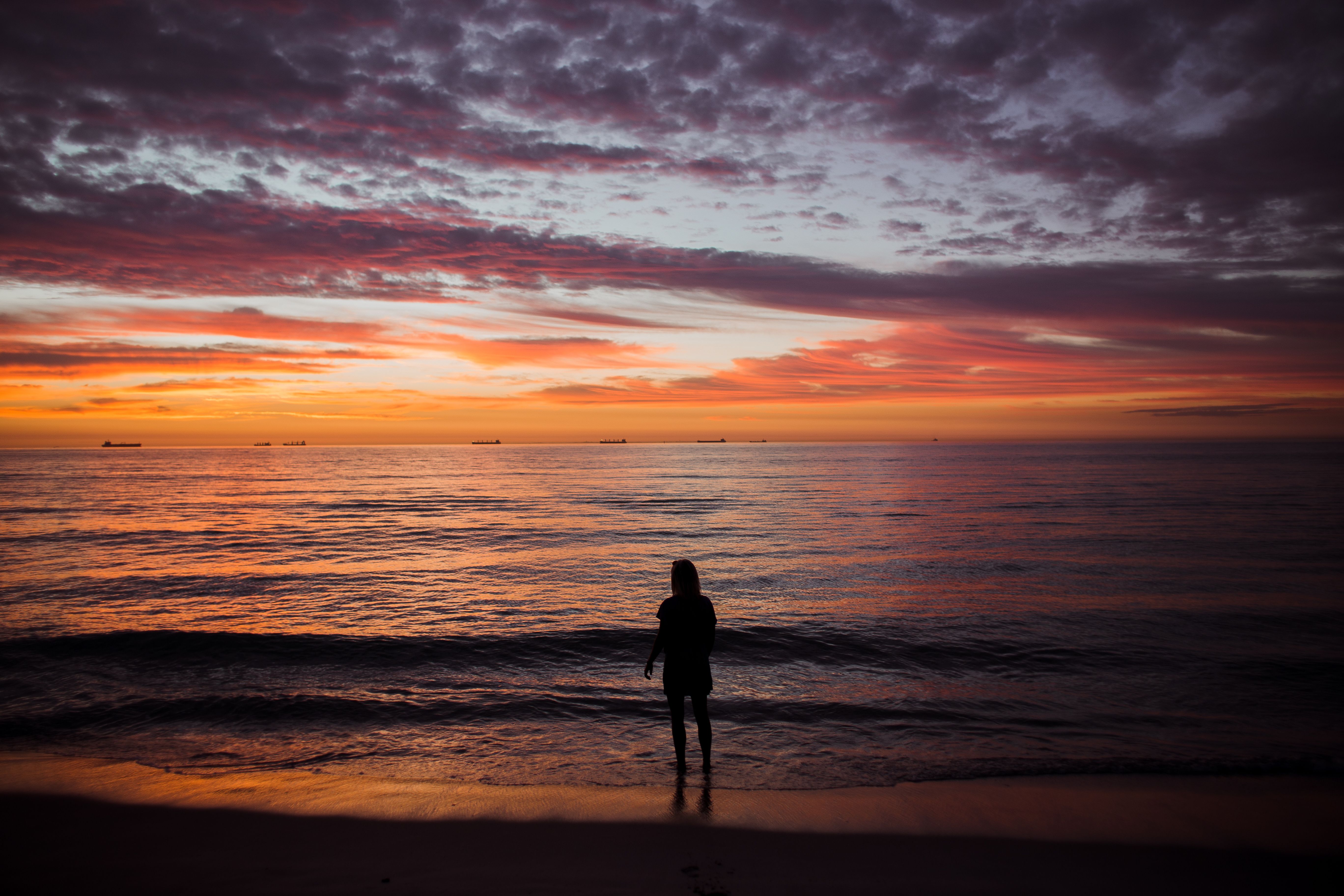 Woman Standing on a Beach at Sunset · Free Stock Photo