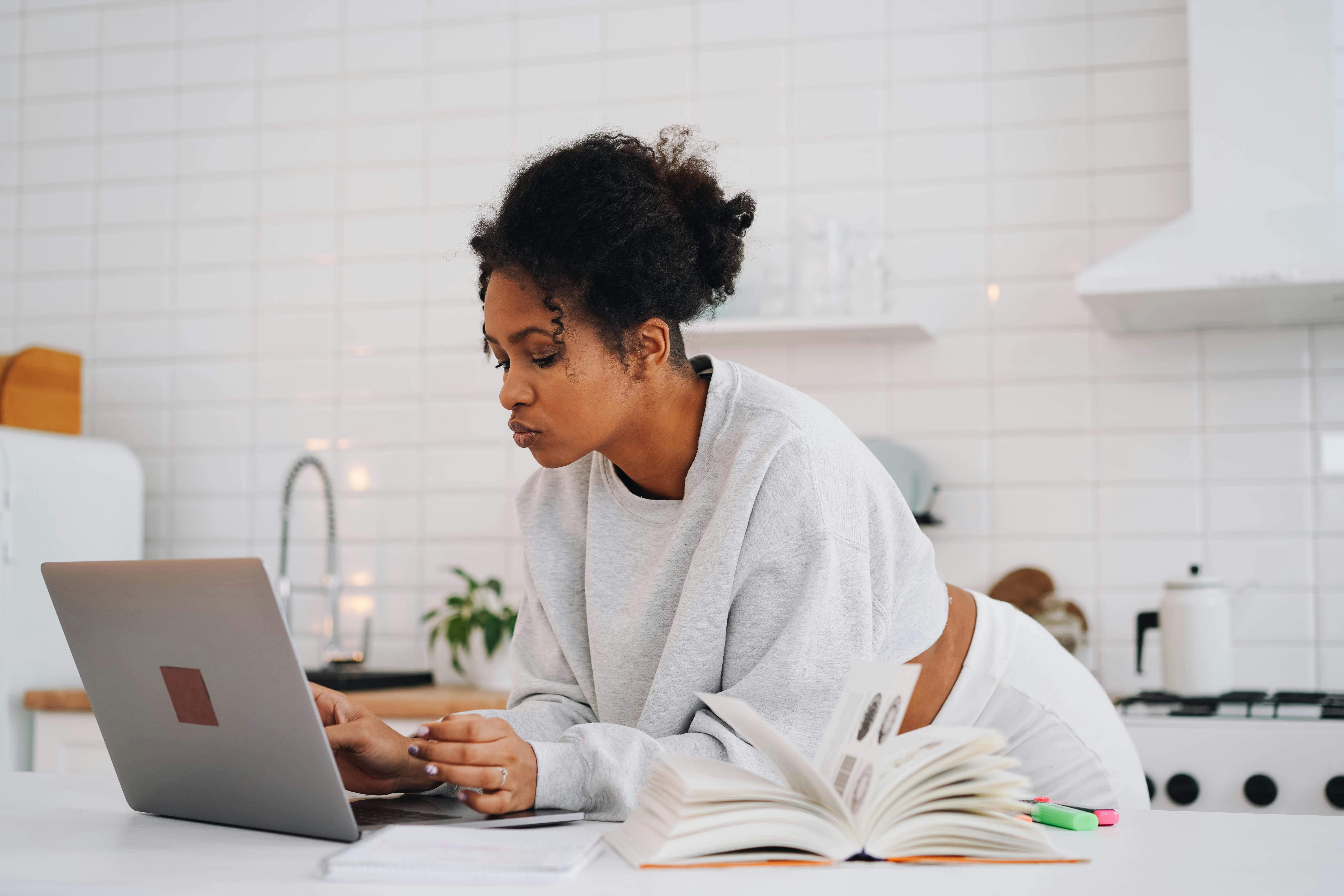 Woman in White Sweater Using a Laptop at Home · Free Stock Photo