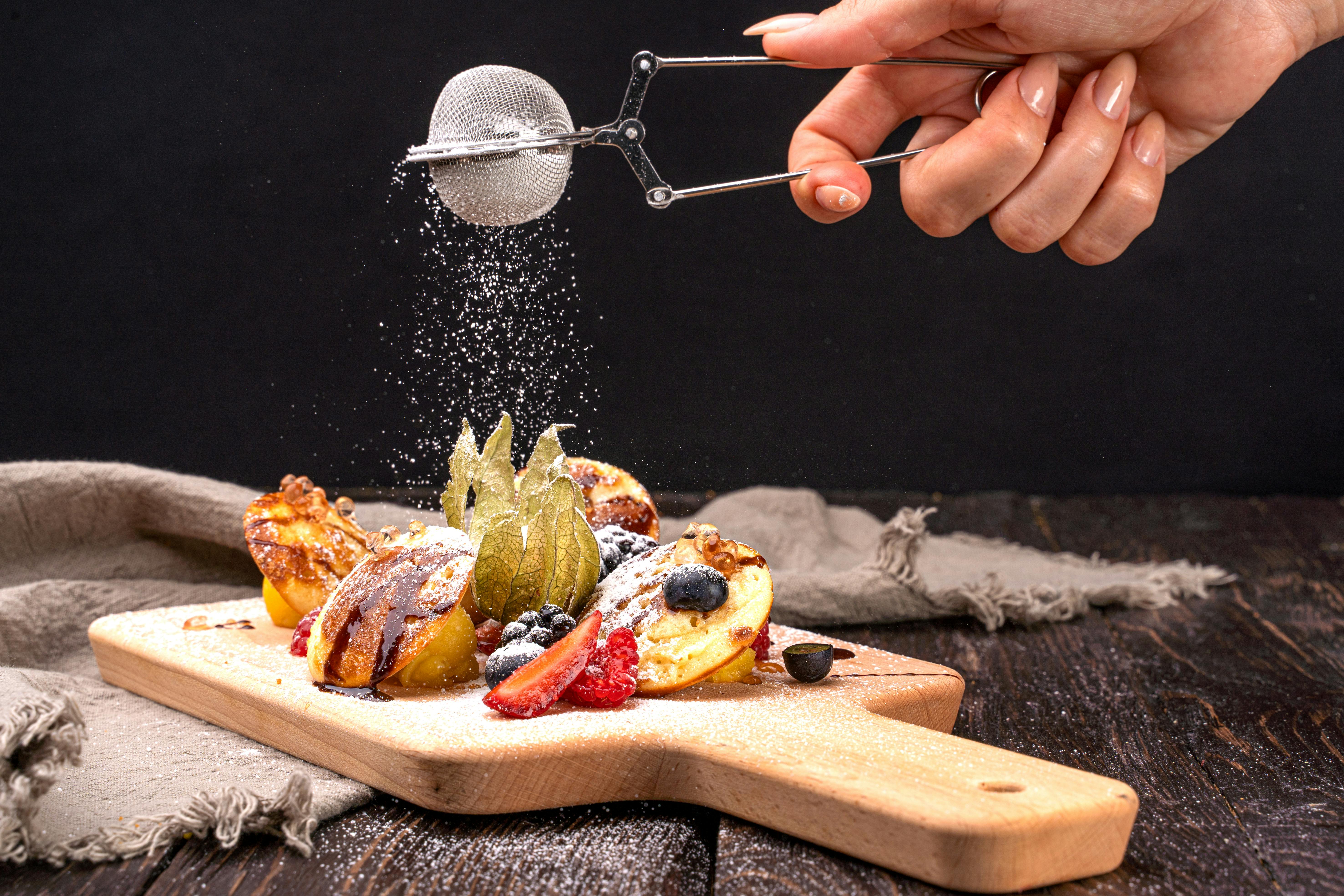 A Hand Sprinkling Flour on the Food Using Strainer · Free Stock Photo