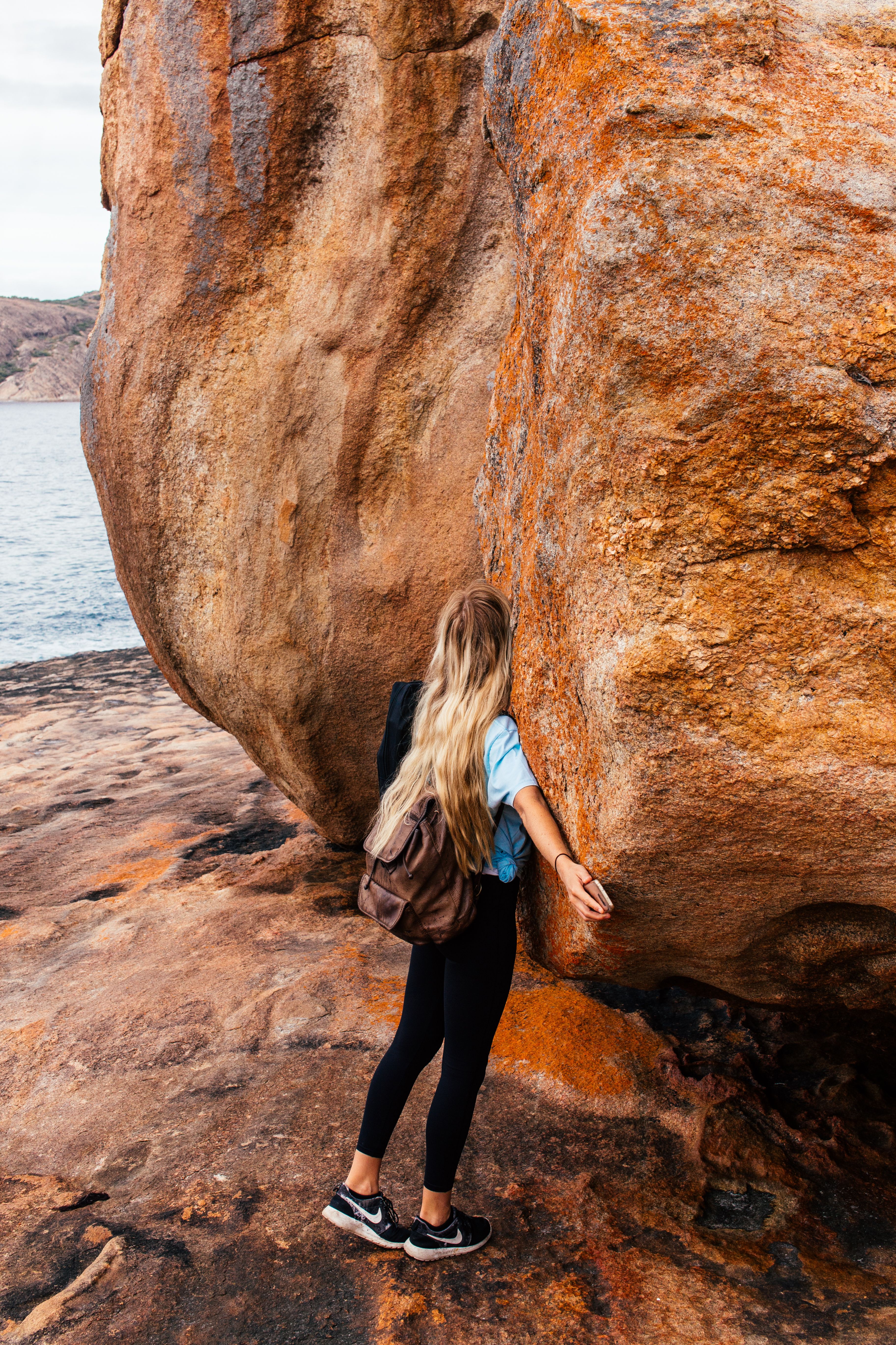 A Person Hugging a Brown Rock Formation · Free Stock Photo