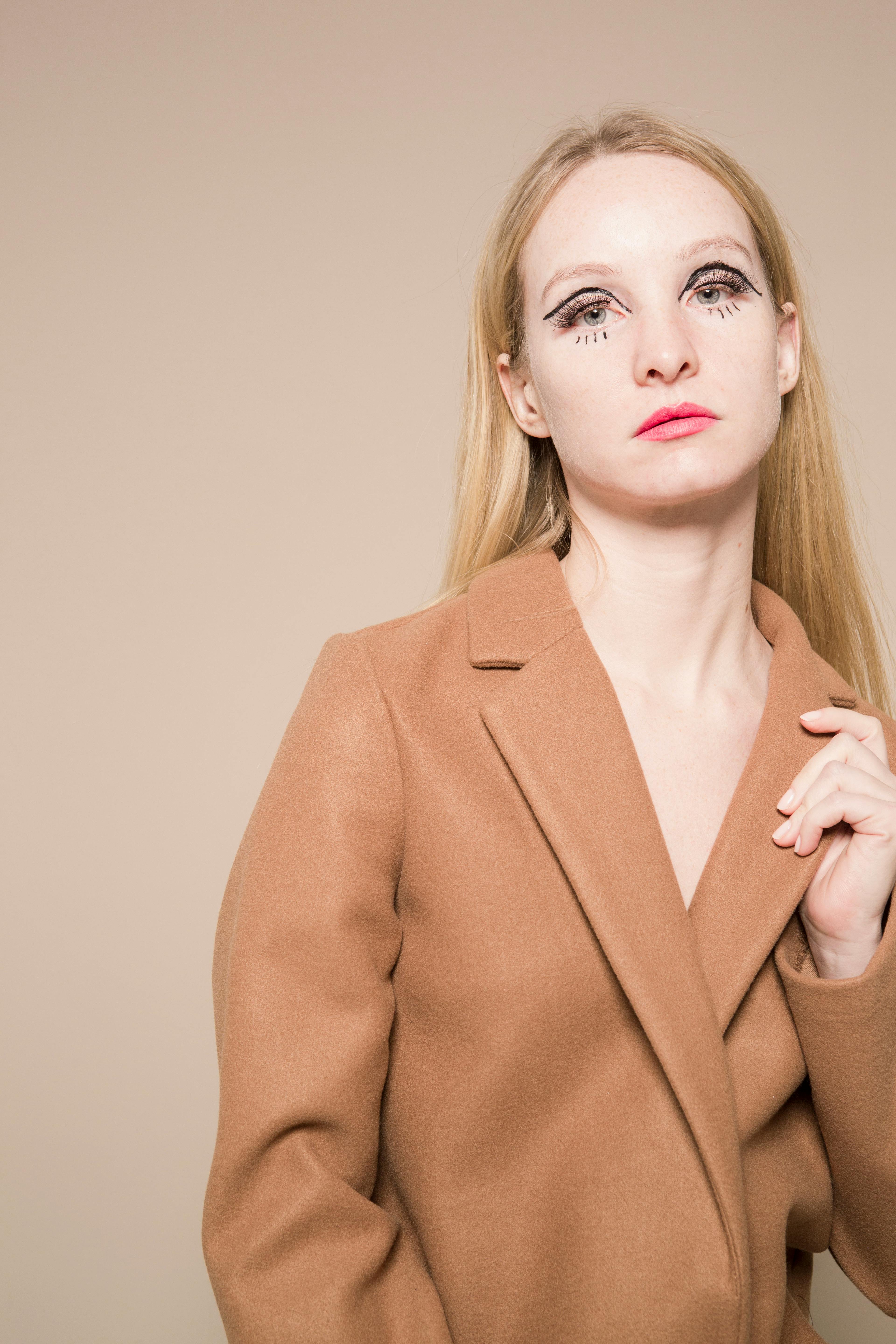 Elegant woman with extravagant makeup touching stylish beige coat ...