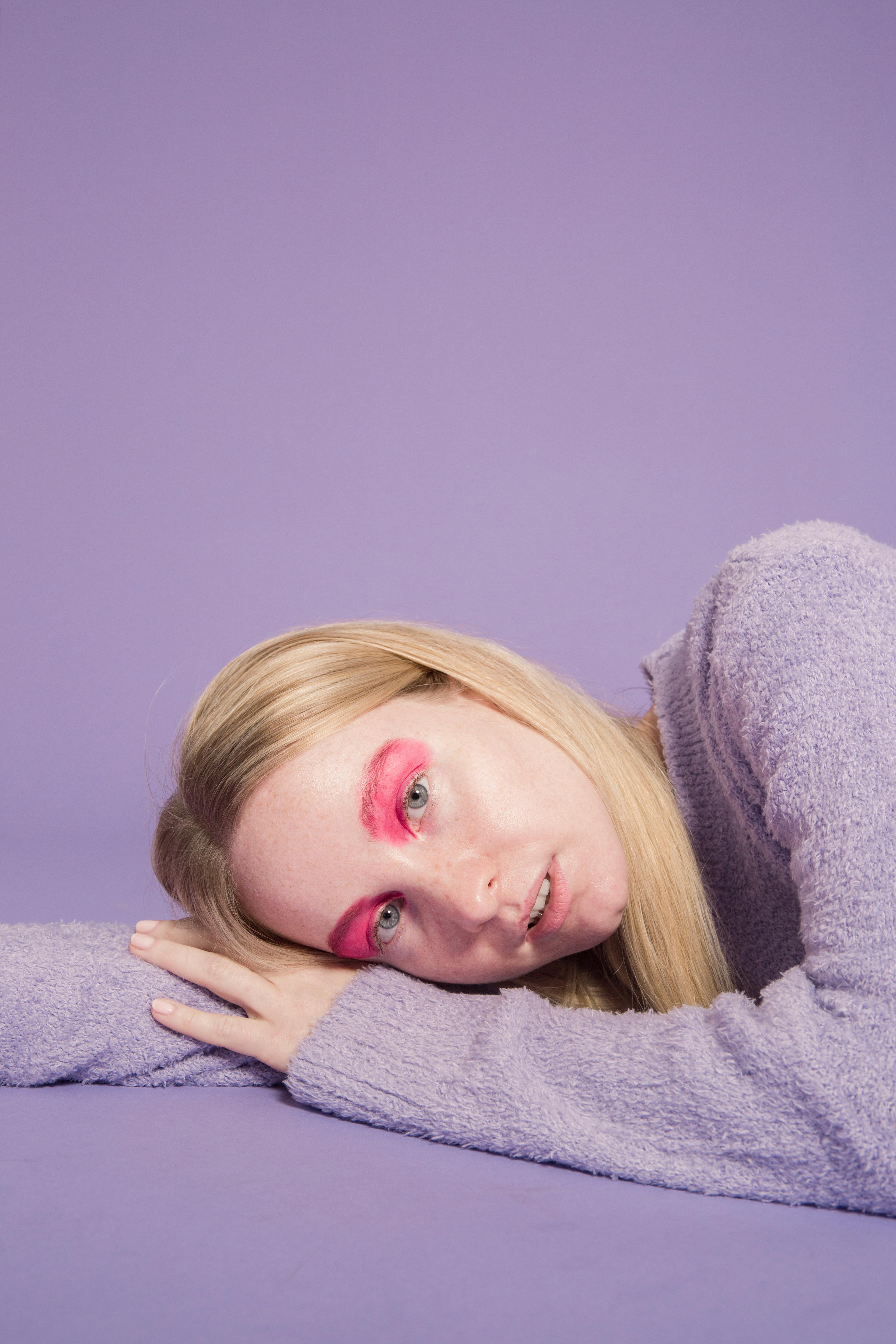 Emotionless woman with colorful makeup lying in studio · Free Stock Photo
