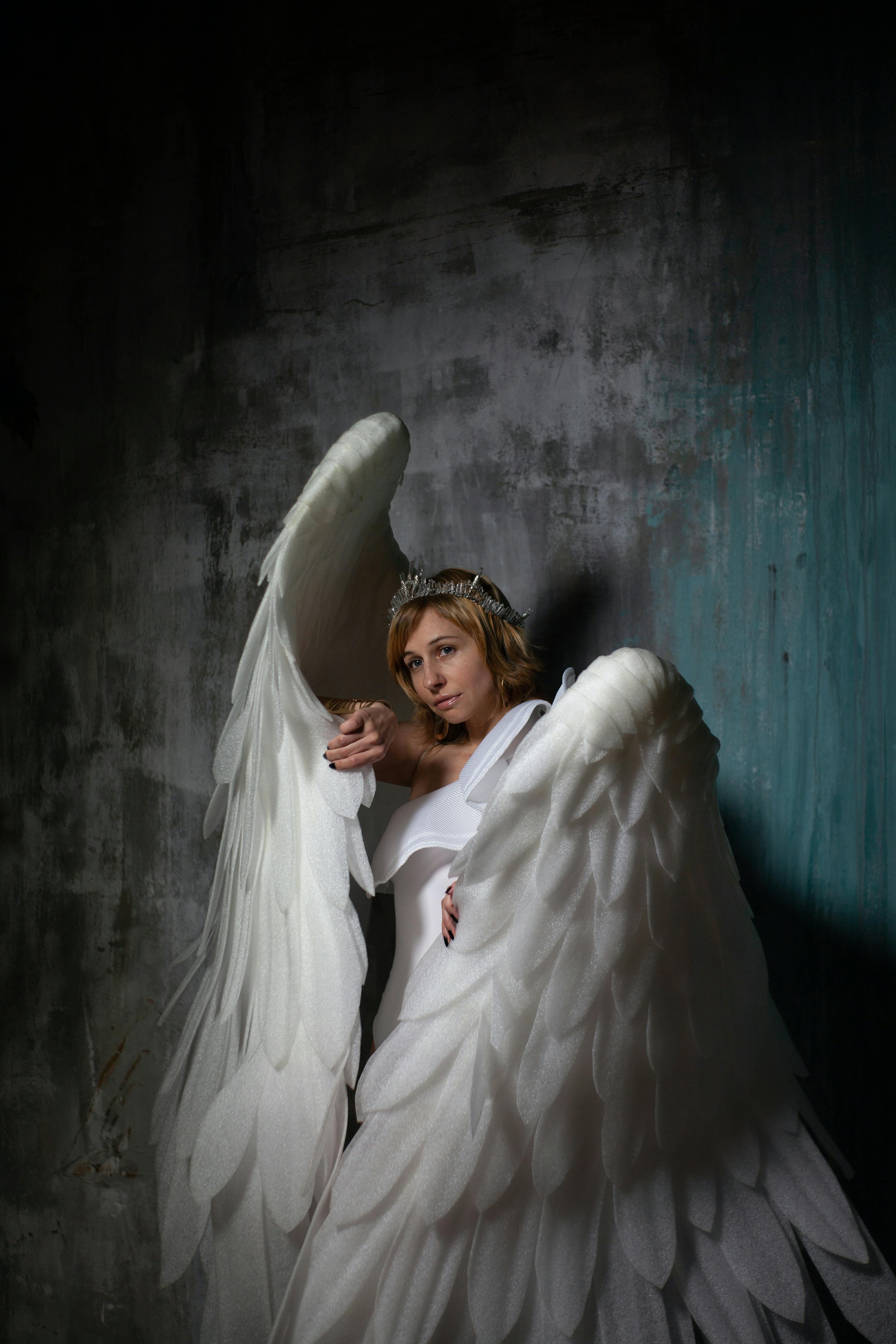 Tender model with angel wings against grunge wall · Free Stock Photo