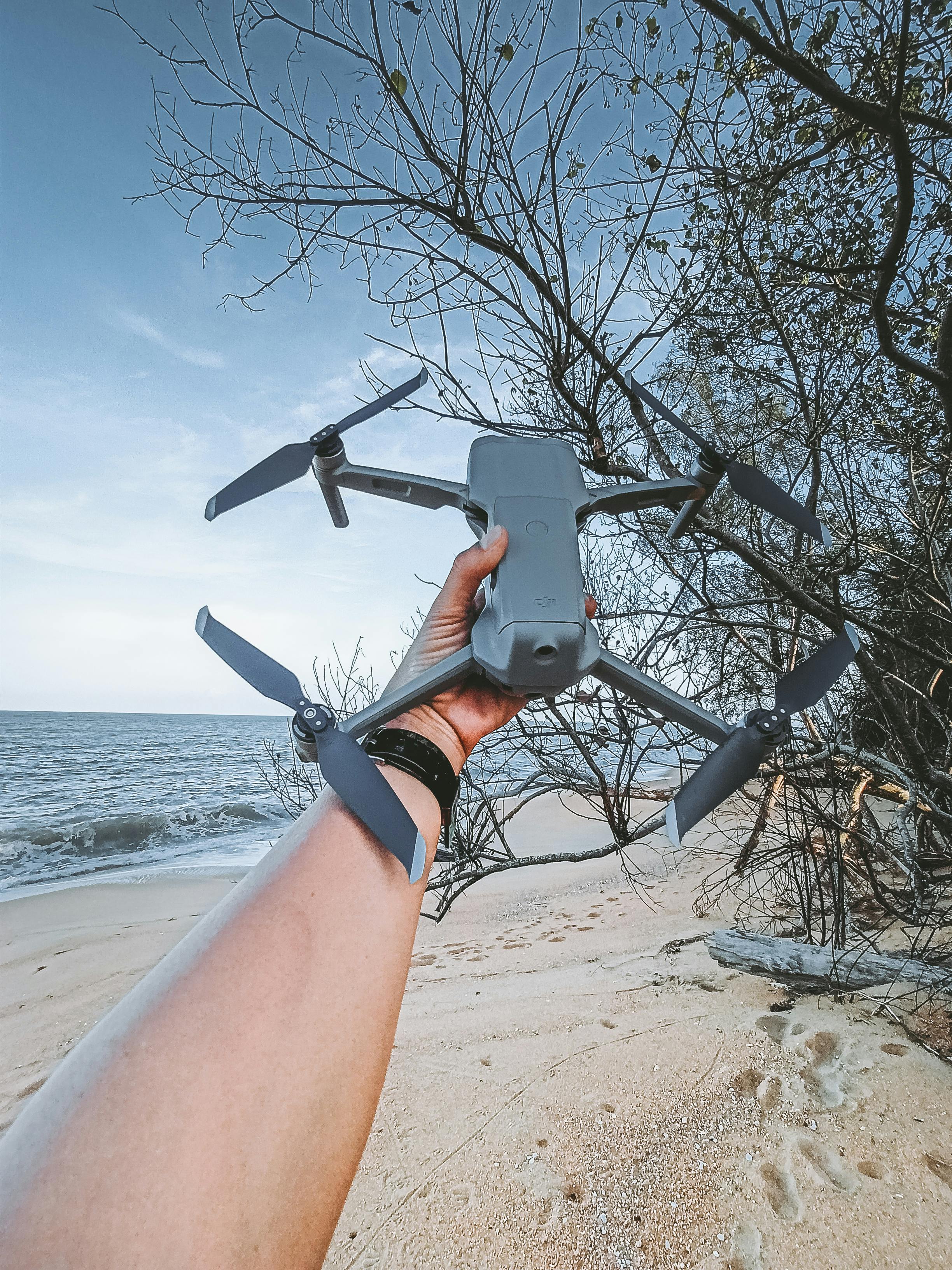 Anonymous tourist launching drone on sandy seashore · Free Stock Photo