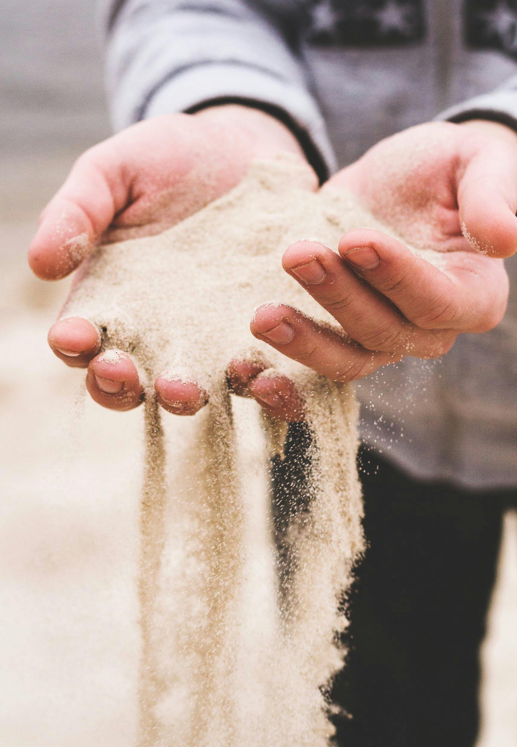 Man stiffing sand from hands on coast · Free Stock Photo