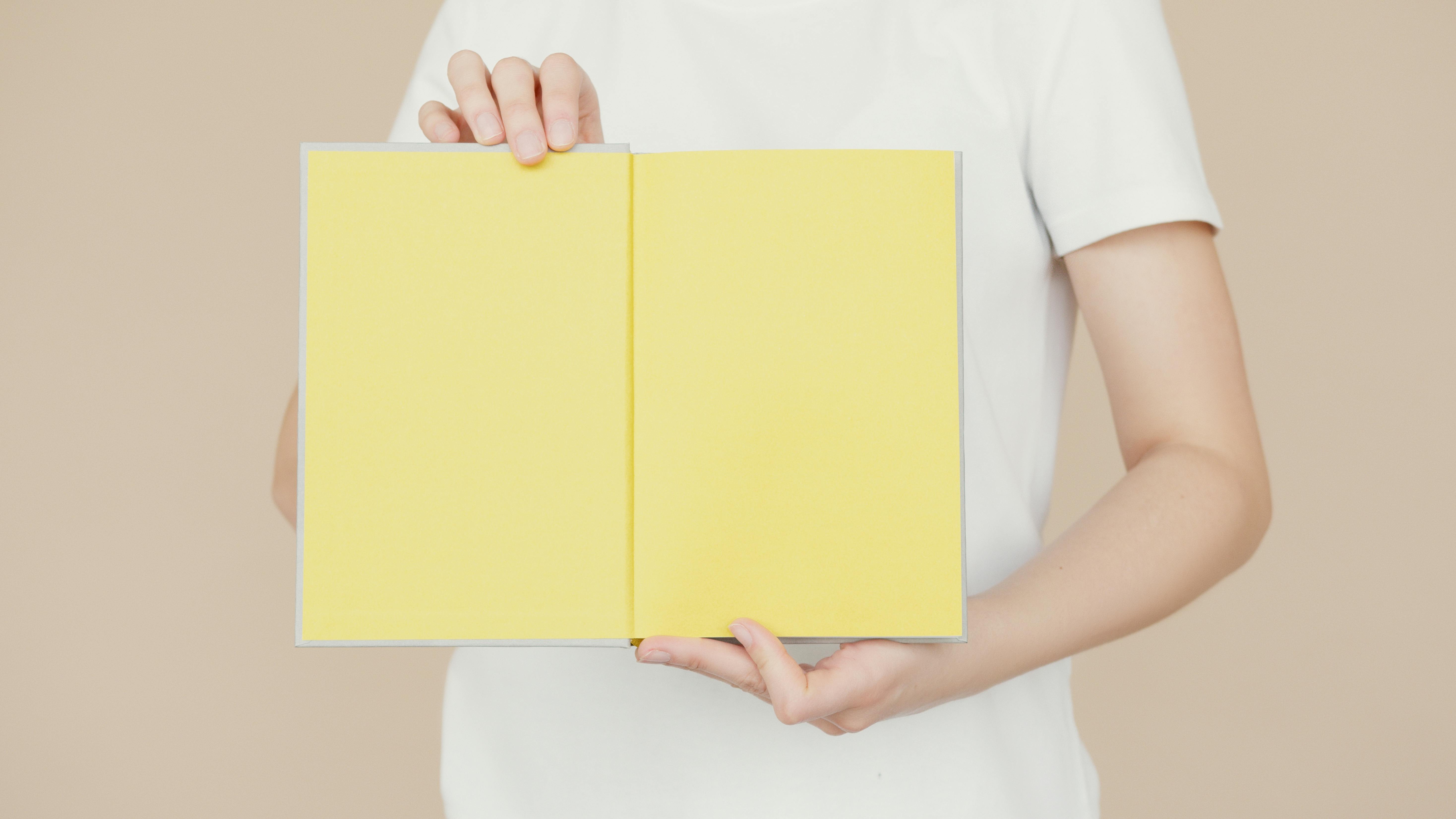 Hand Touching a Beige Notebook · Free Stock Photo